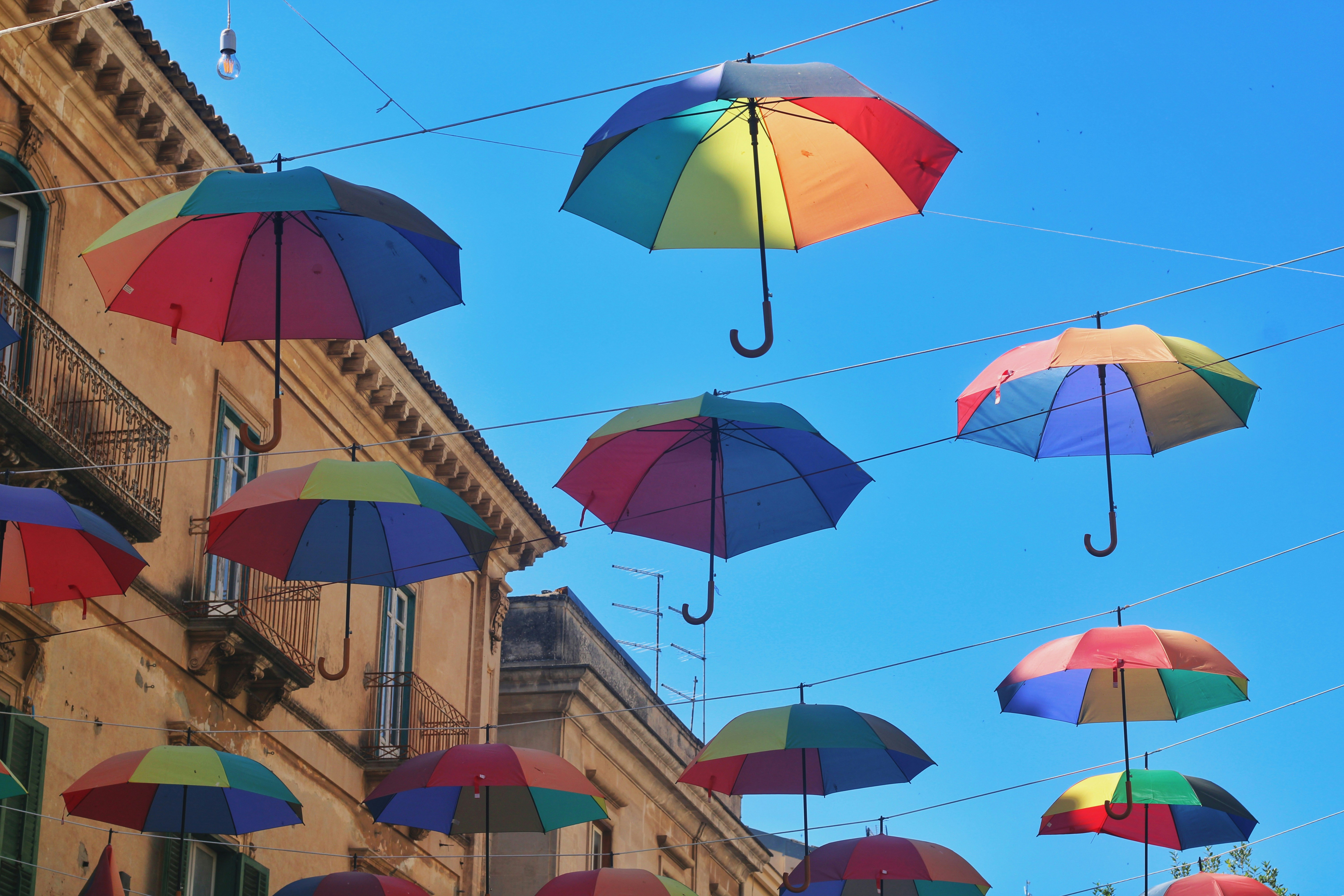 Colorful umbrellas suspended above a street against a clear blue sky.