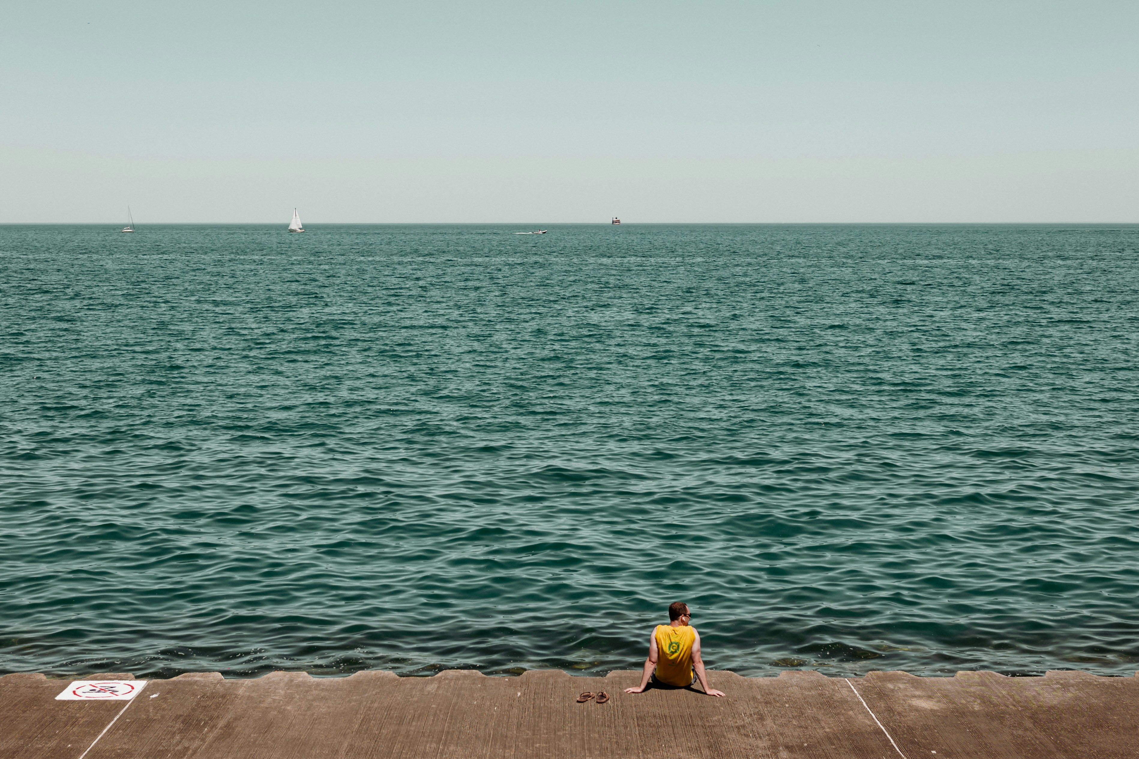 Edge of Stillness: A lone figure on a weathered pier facing the sea