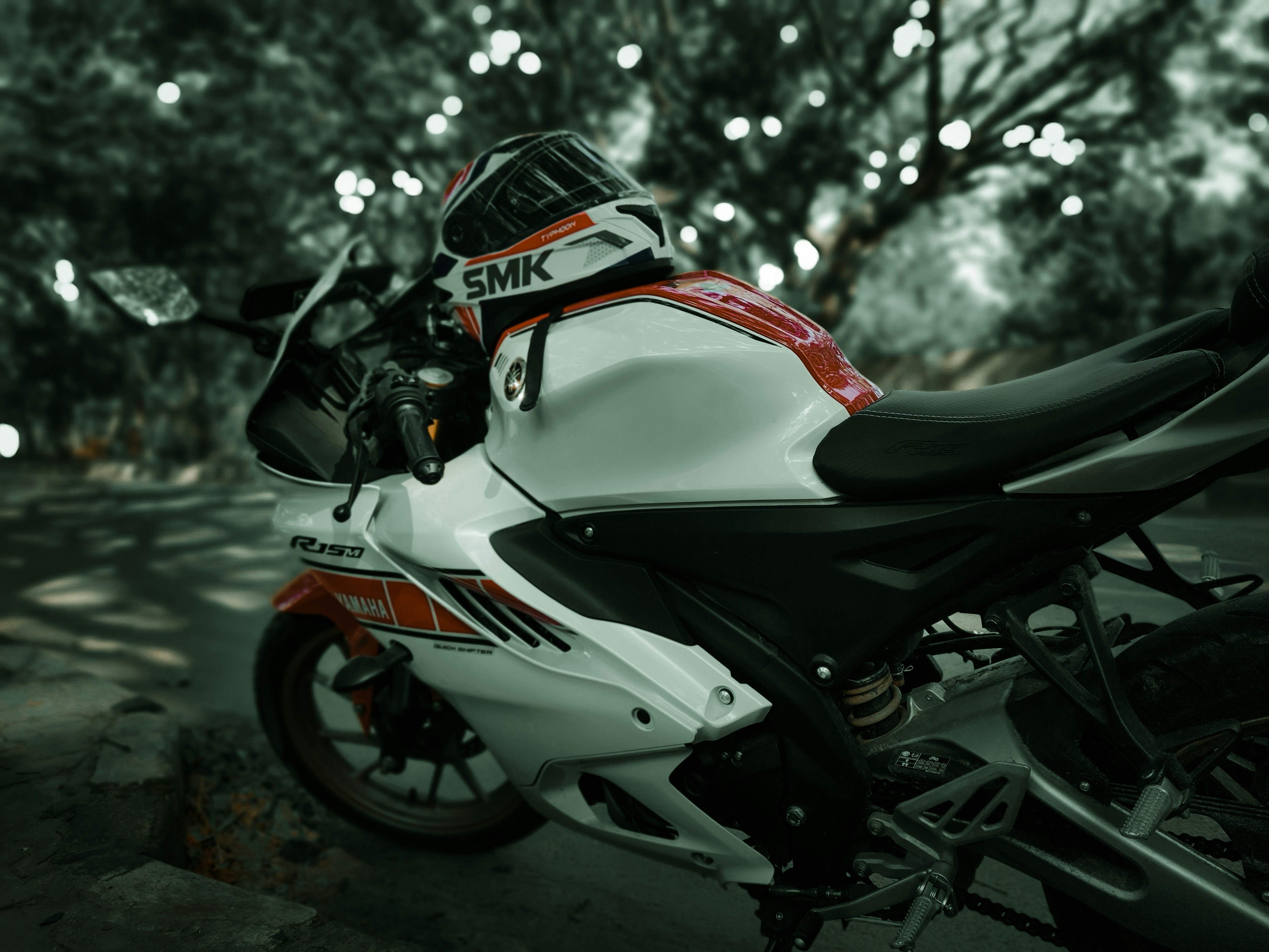 White and red motorcycle with a matching helmet, parked on a shaded road.