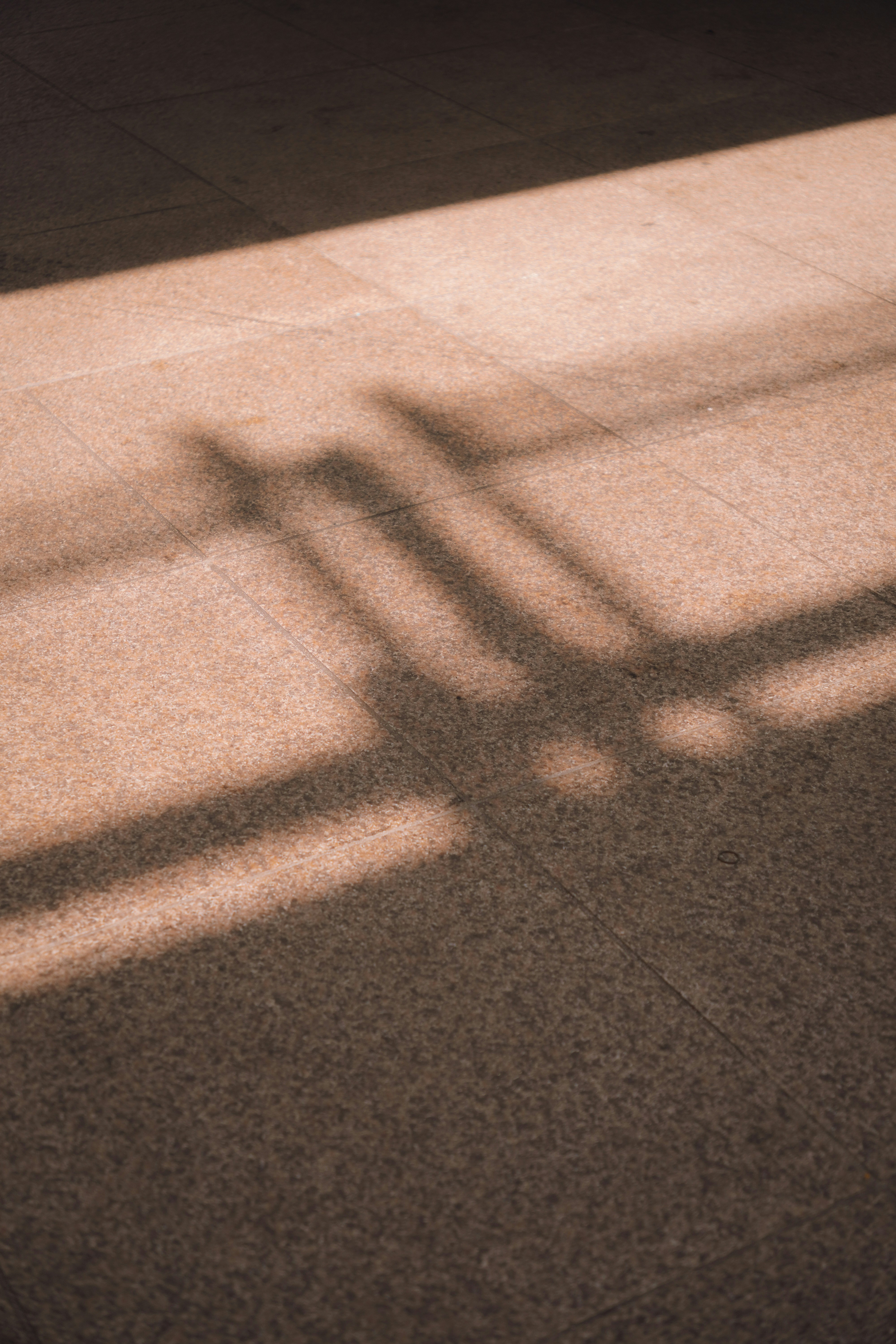 Soft shadows cast on a textured floor, highlighting geometric patterns created by natural light.