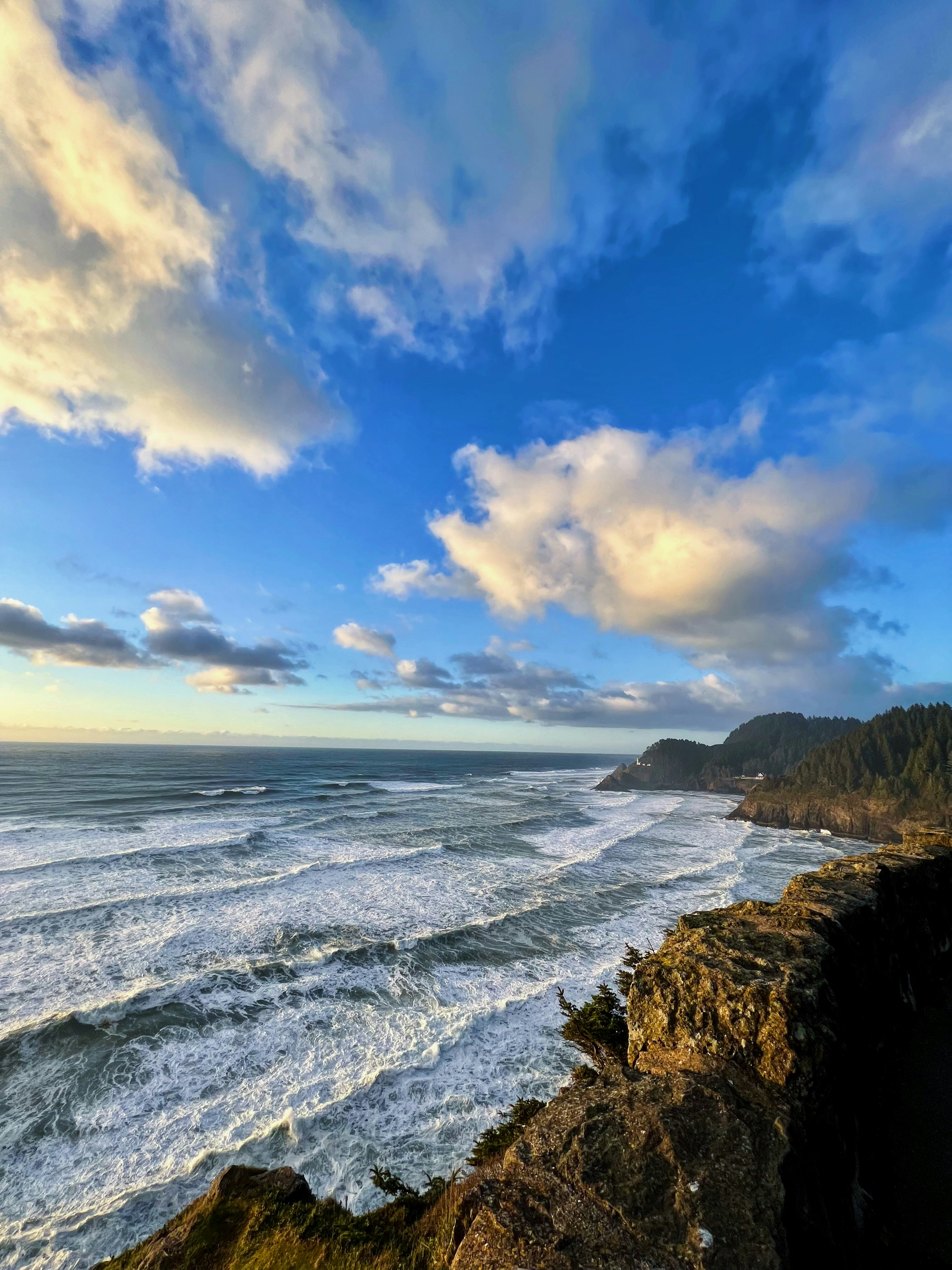 Horizon Echoes: Sunlit Clouds Over a Rugged Cliffside Seascape