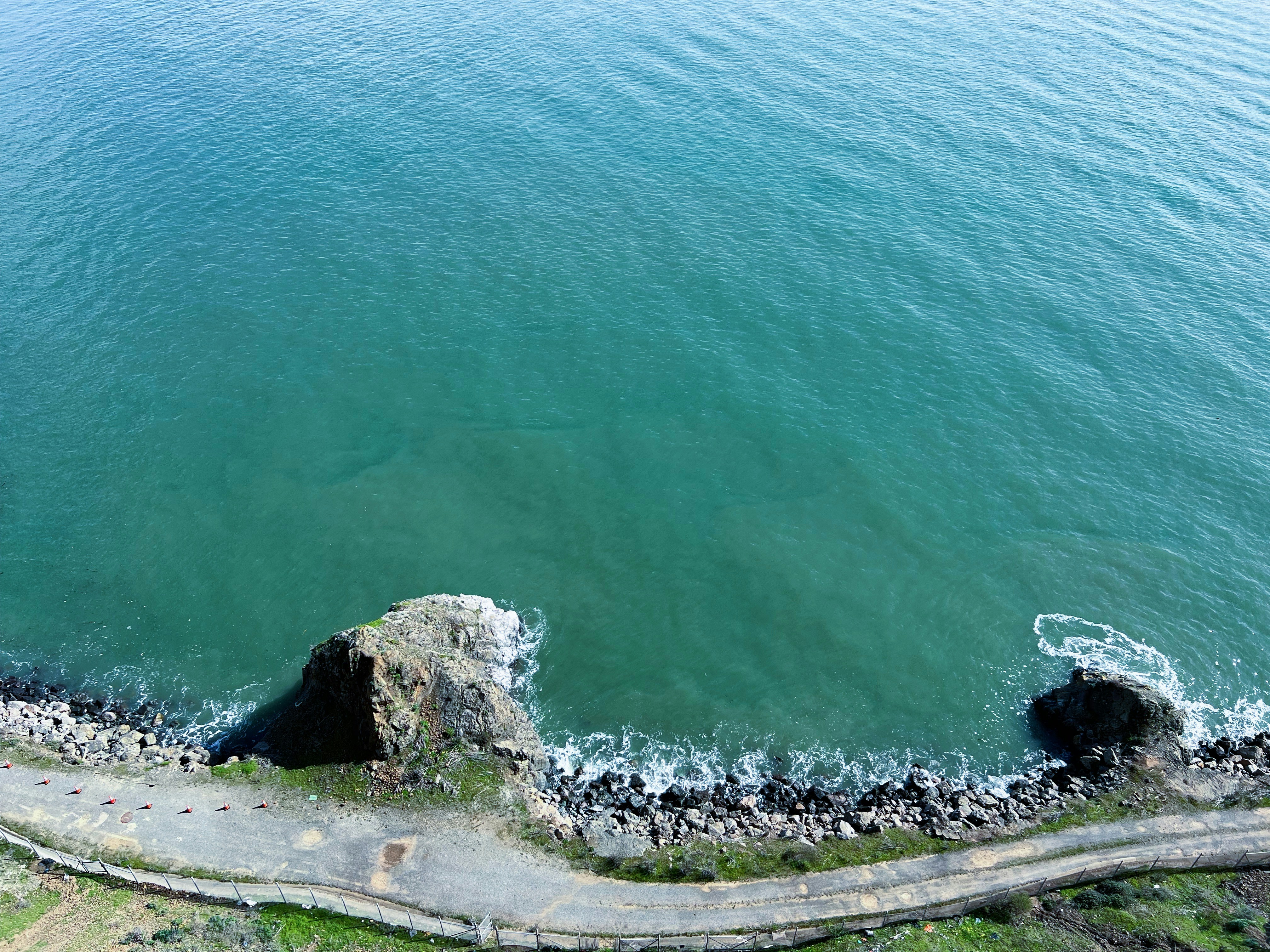 Teal Edge: Stone Sentinels Along a Curved Seaside Path