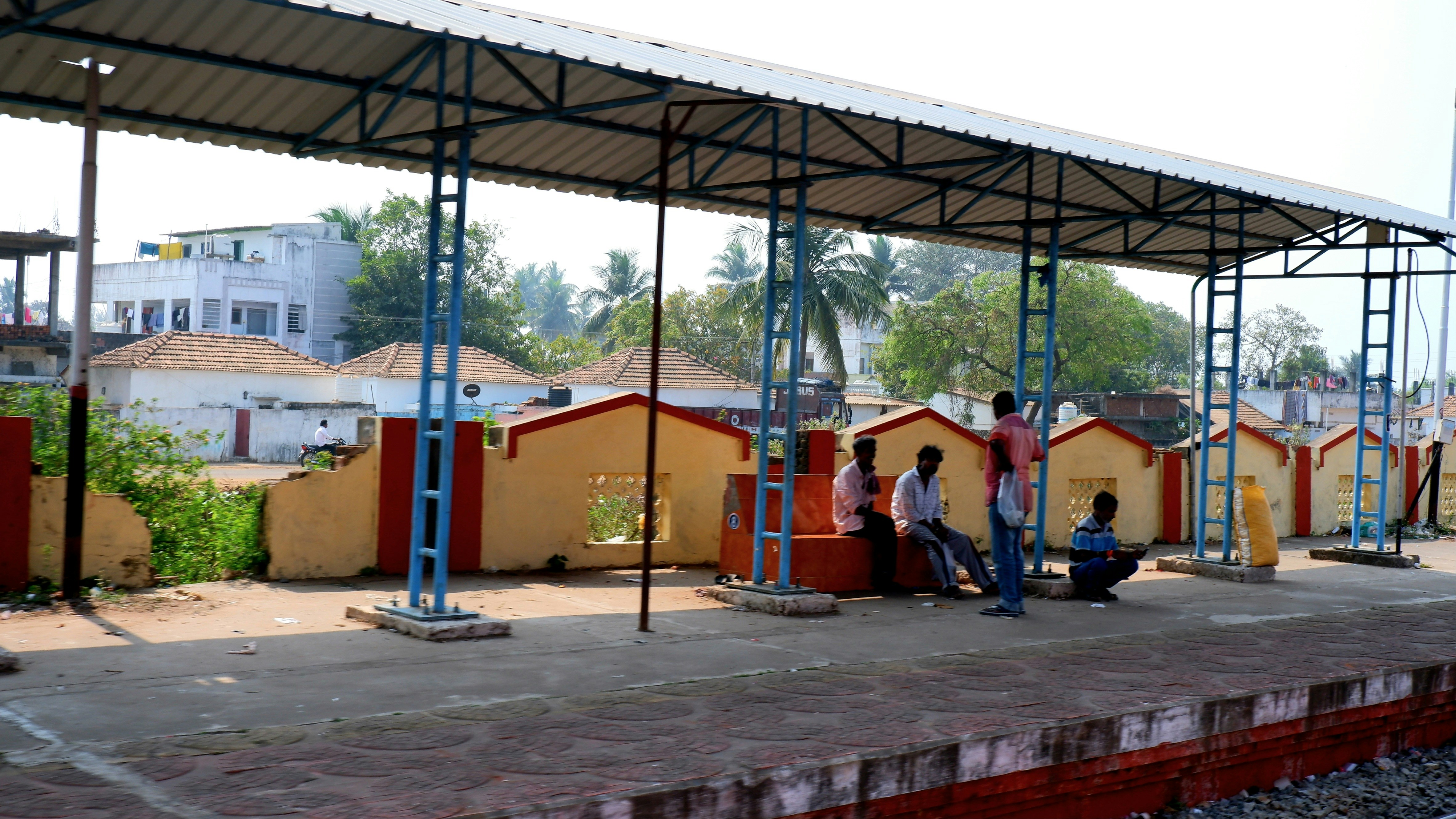 Morning Pause Under a Blue-Framed Shelter: Quiet Exchange at a Local Transit Stop