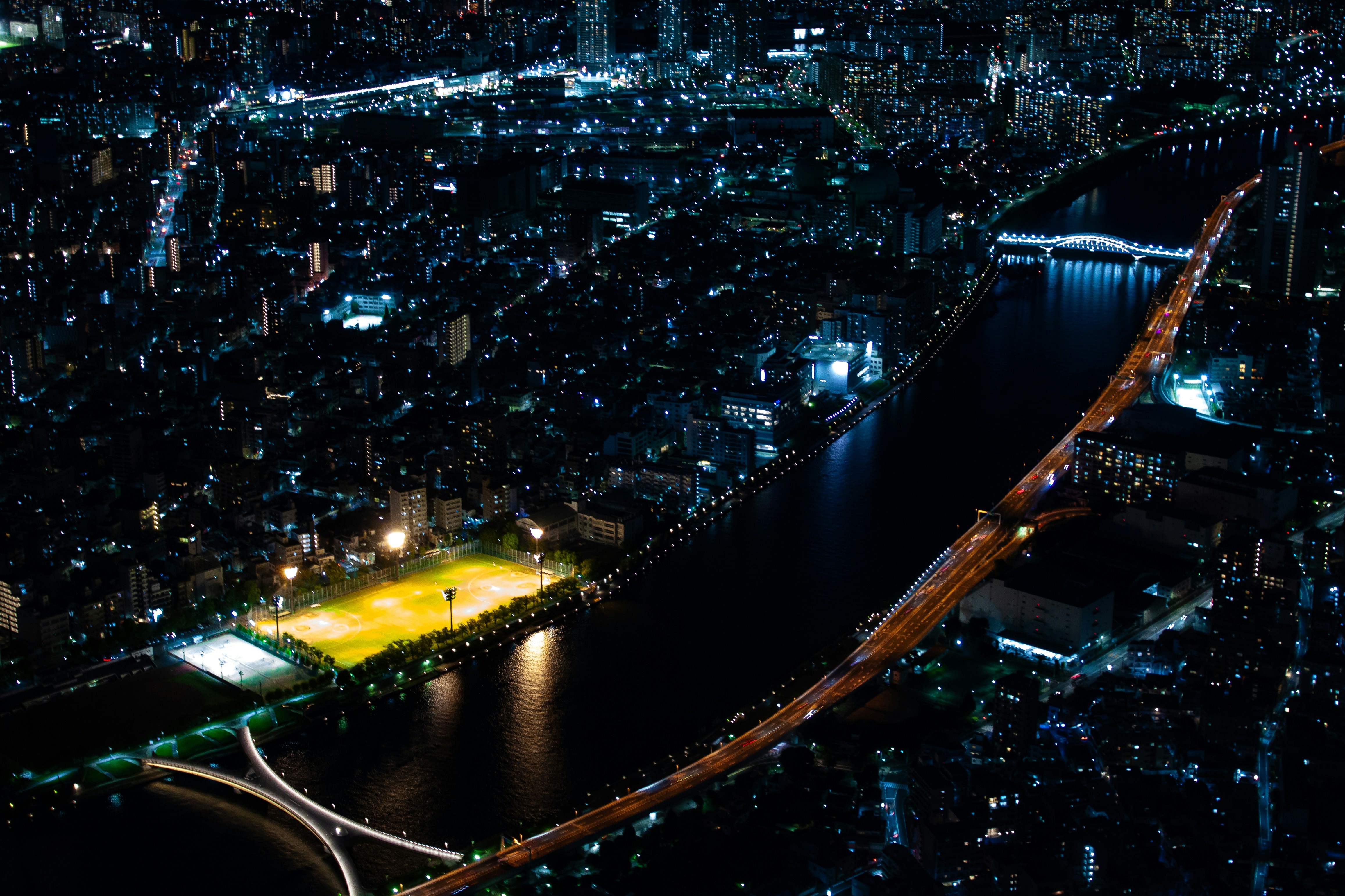 Aerial Night Pulse: Neon River and Bridge Carved Through the City