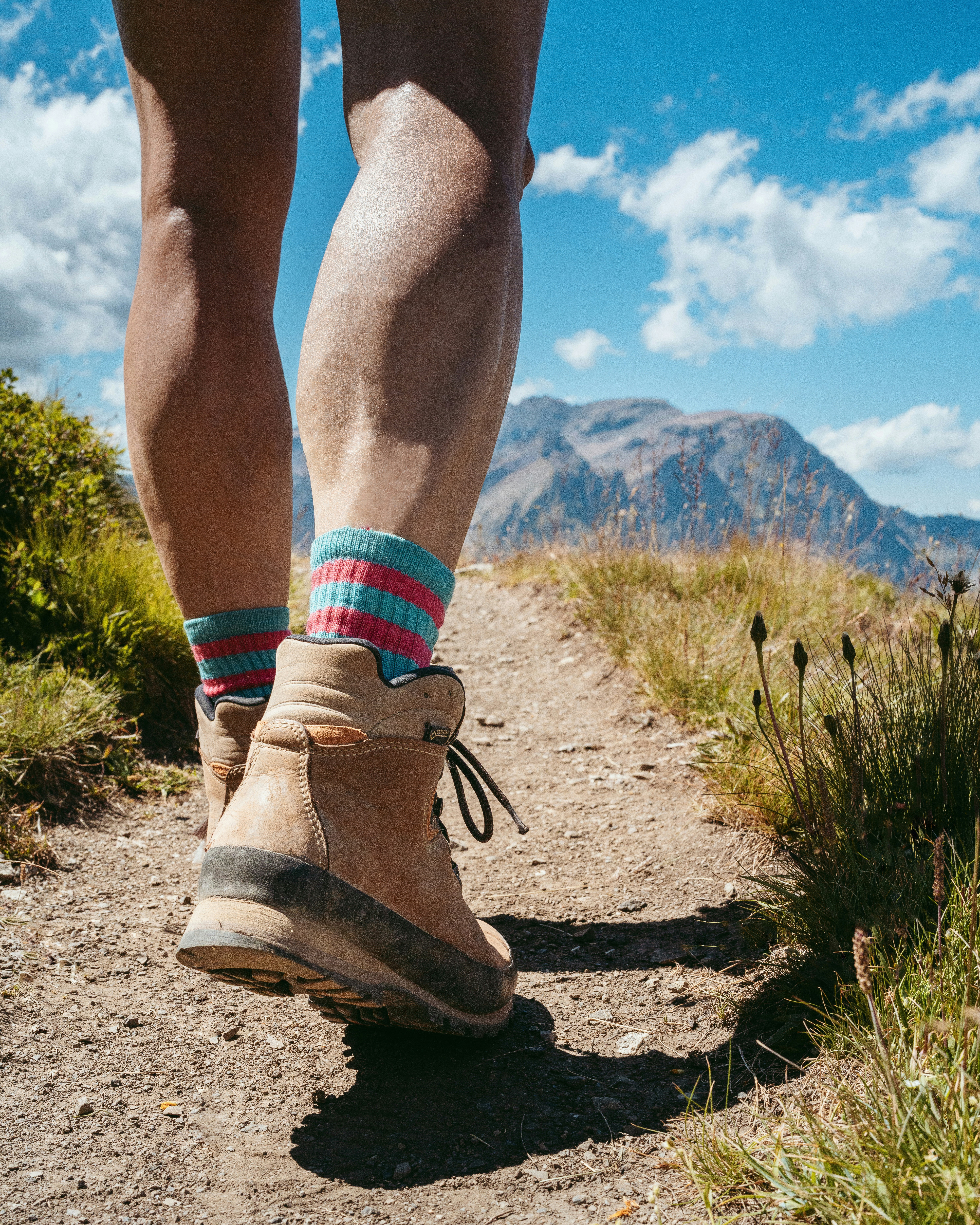 Una persona che cammina su un sentiero sterrato con una montagna sullo ...
