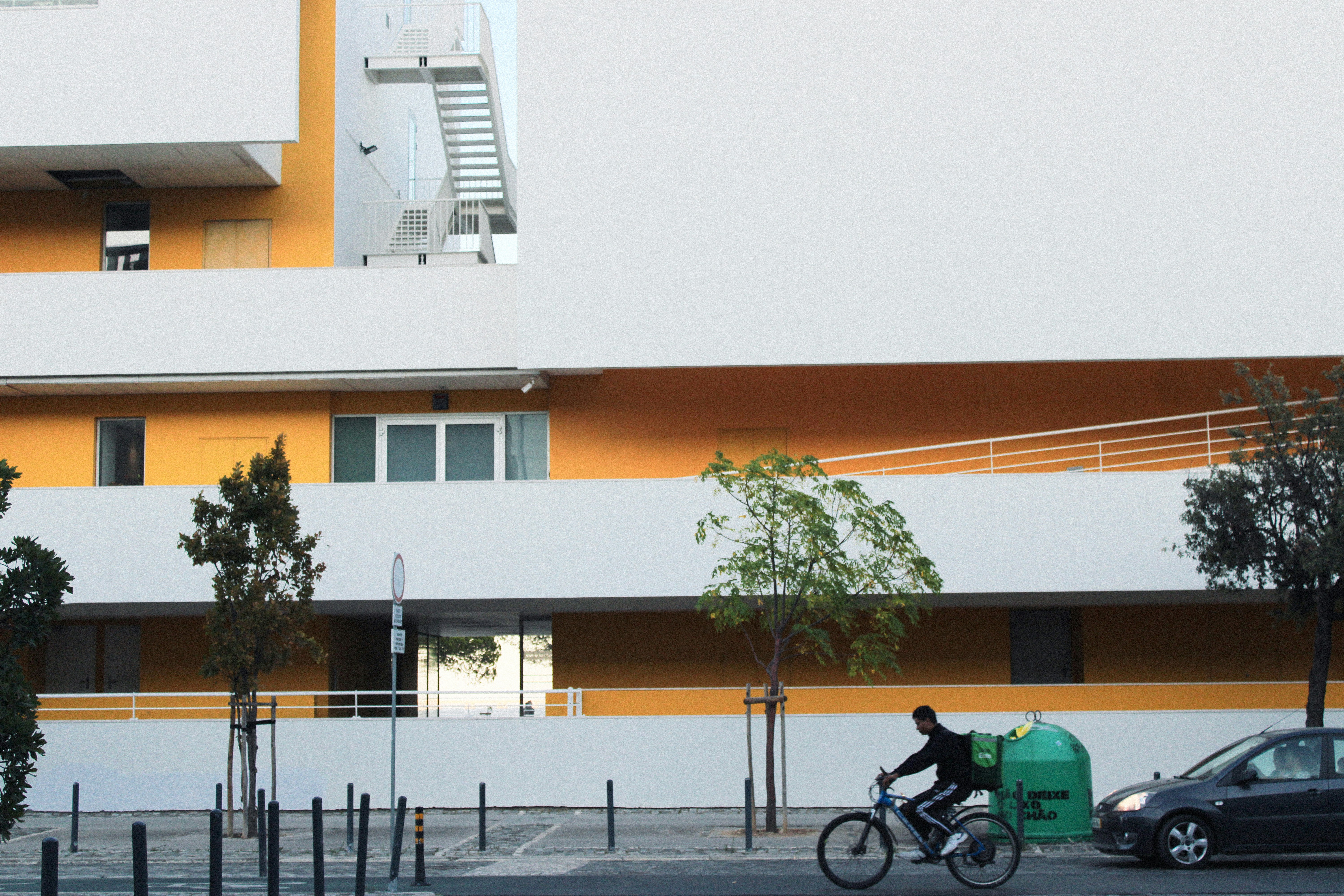 a man riding a bike past a tall building