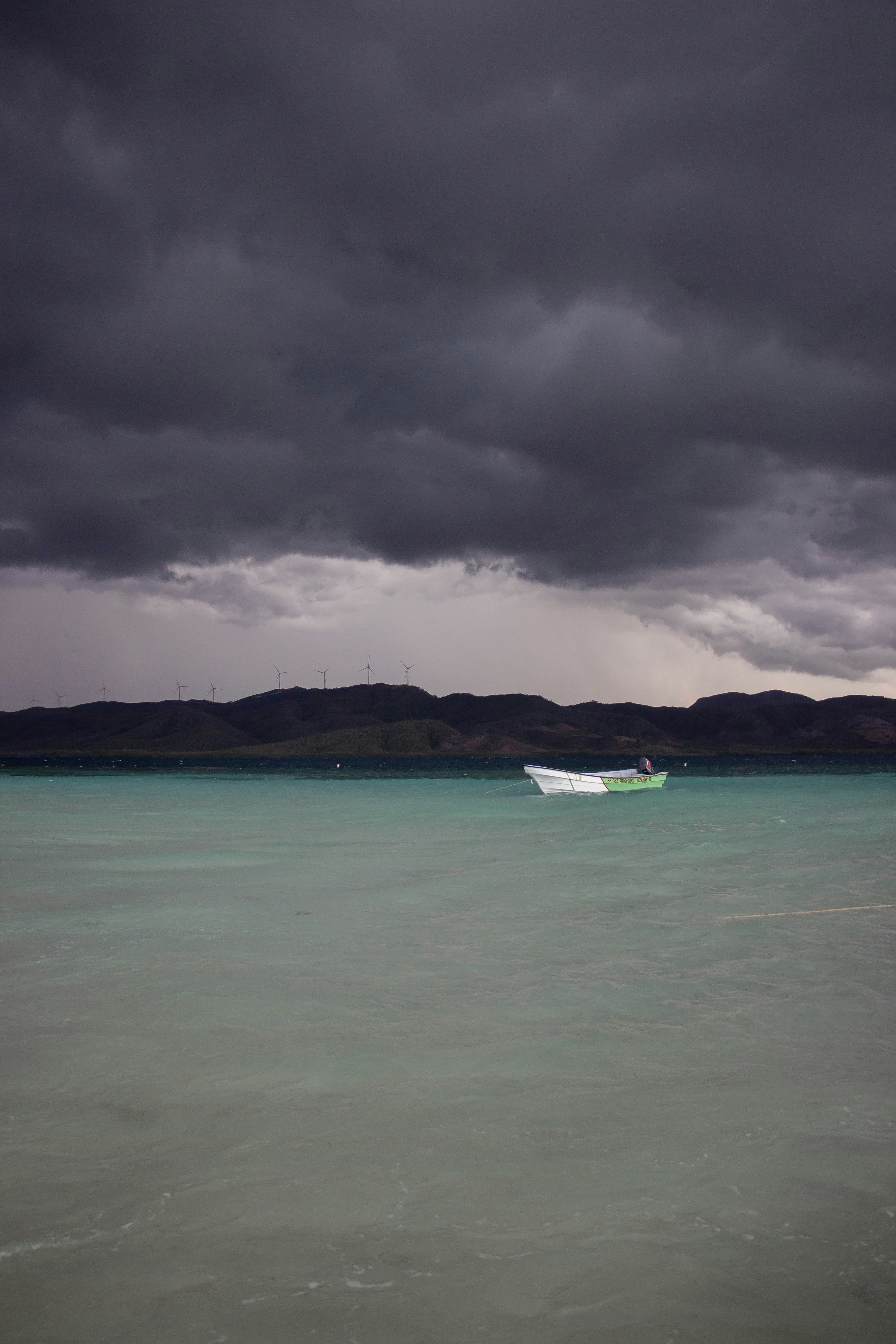 Green-hulled Boat Between Turquoise Waters and Looming Storm Clouds