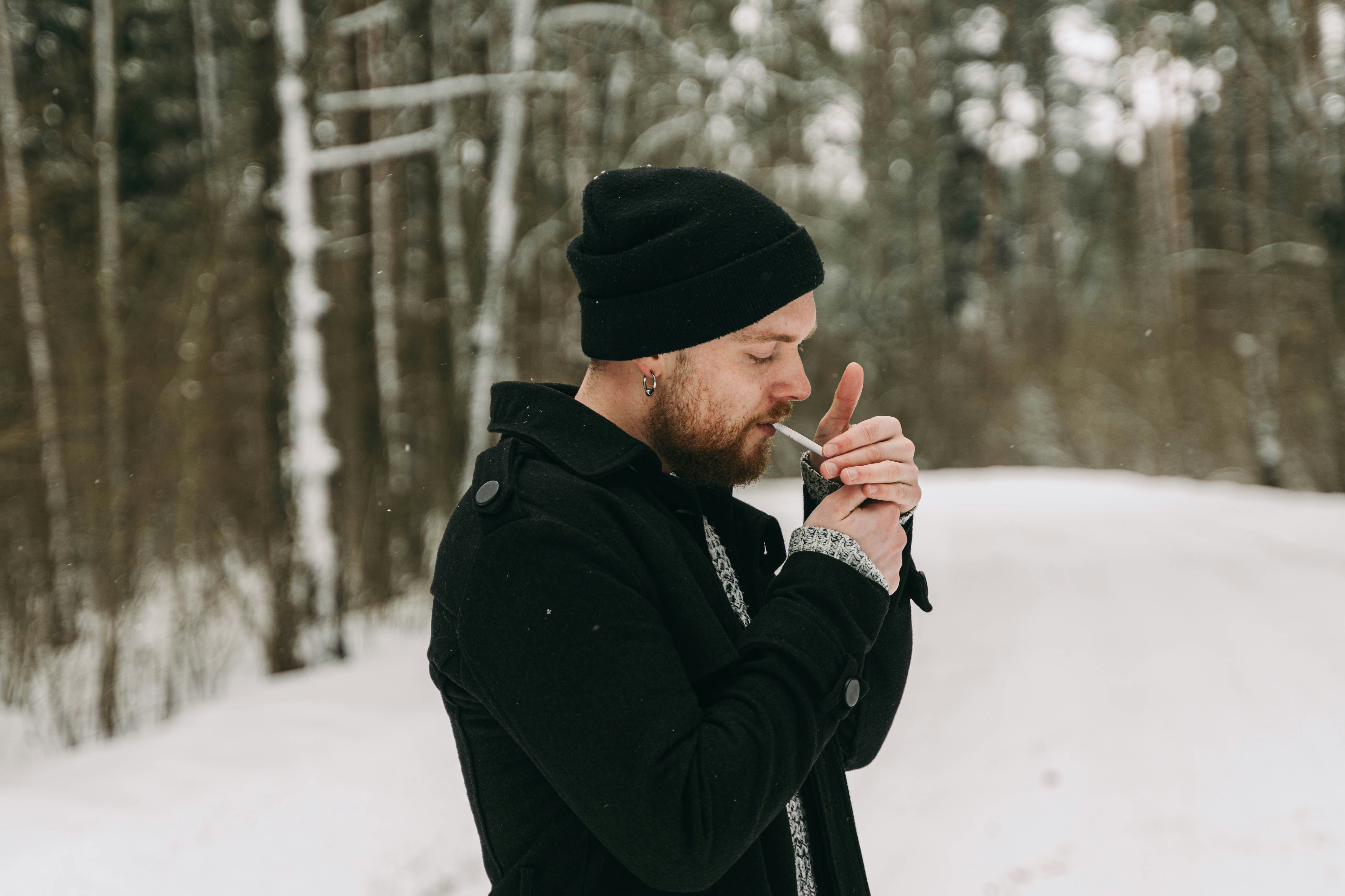 A man standing in the snow smoking a cigarette photo – Free Man Image ...