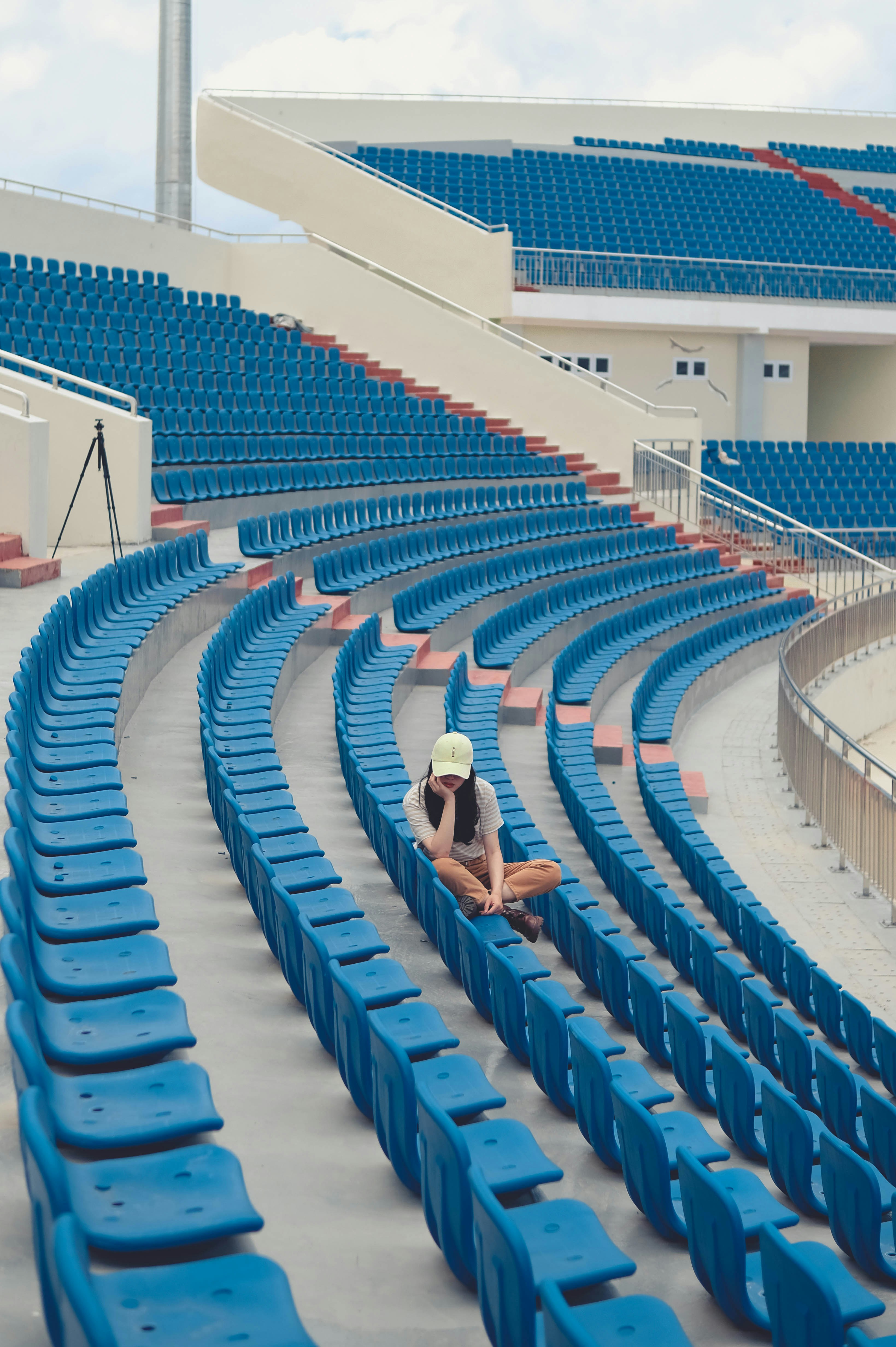 Une femme assise sur les gradins bleus d’un stade photo – Photo Chaises ...