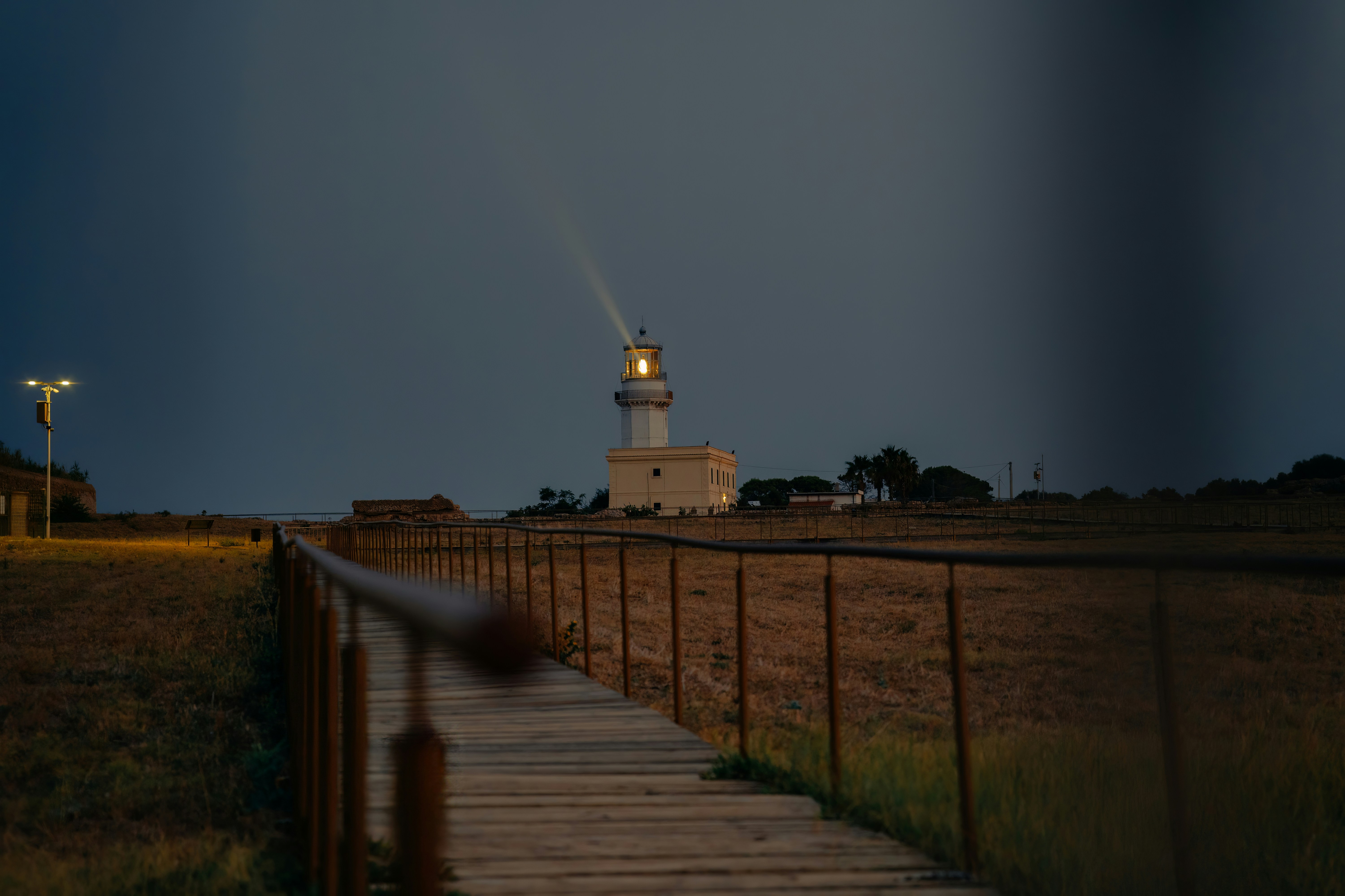 End of the Walk: Night Beacon over a Quiet Coastal Boardwalk