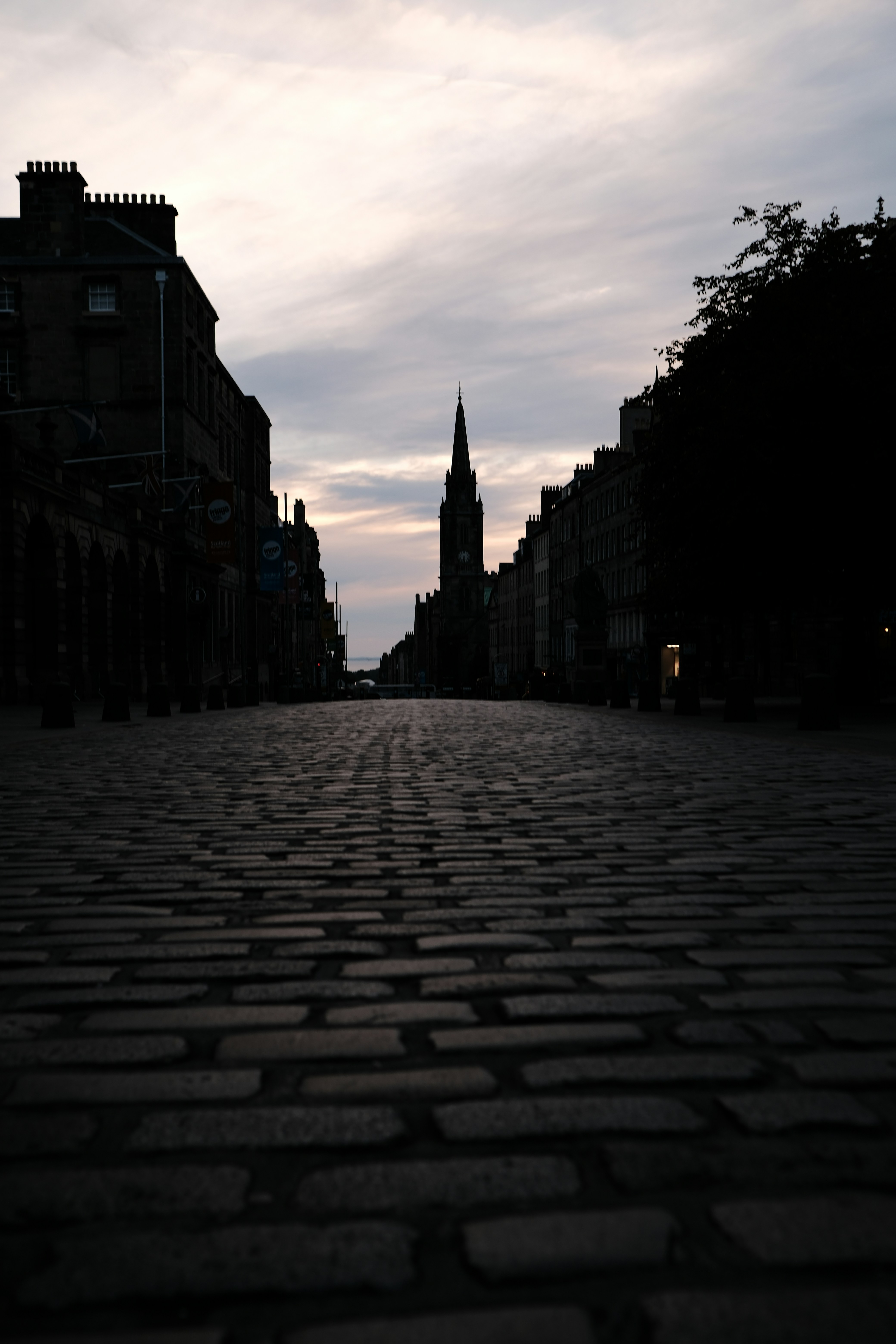 A cobblestone street with a clock tower in the distance photo – Free ...