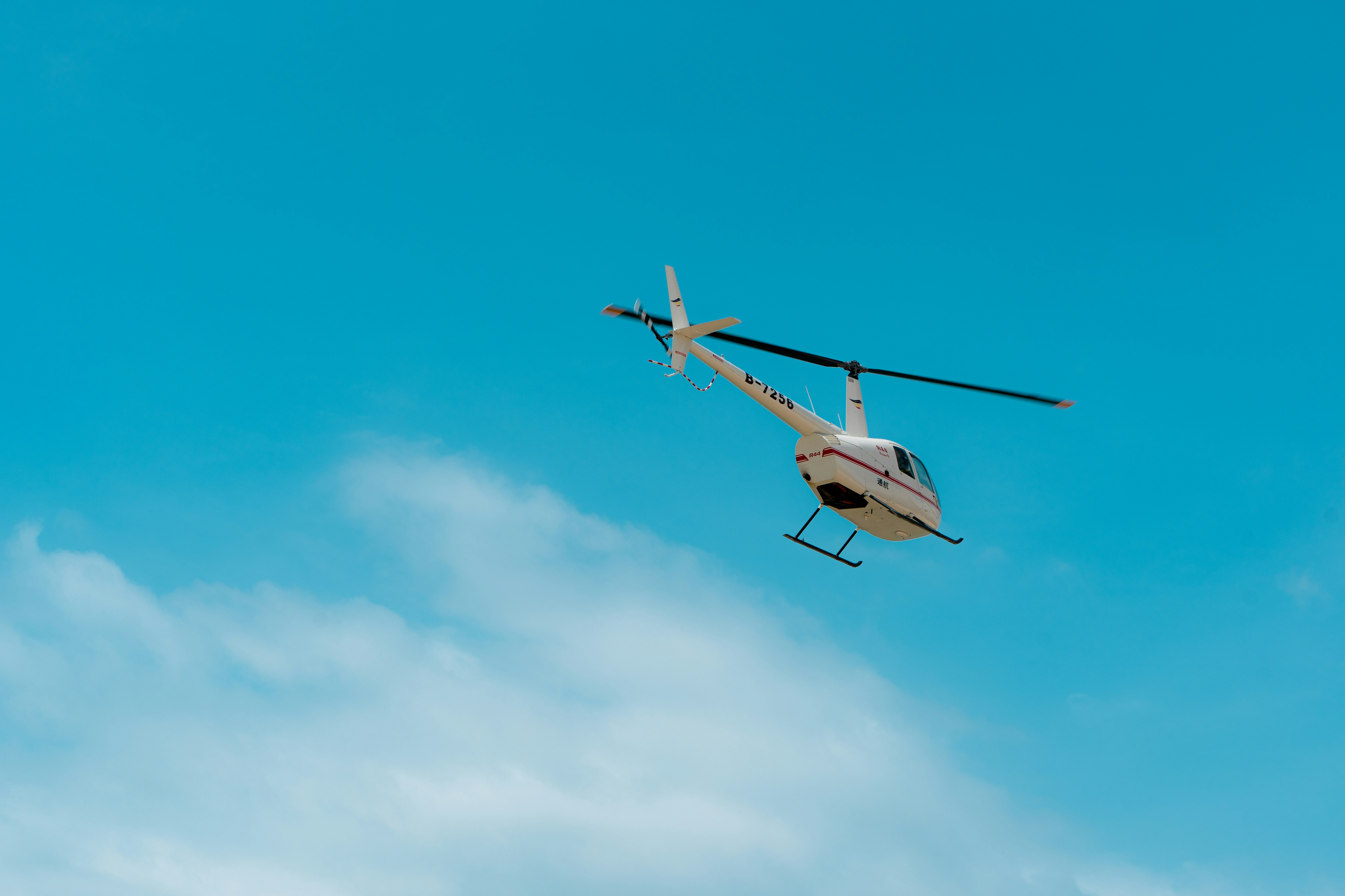 A helicopter flying through a blue sky with clouds photo – Free ...