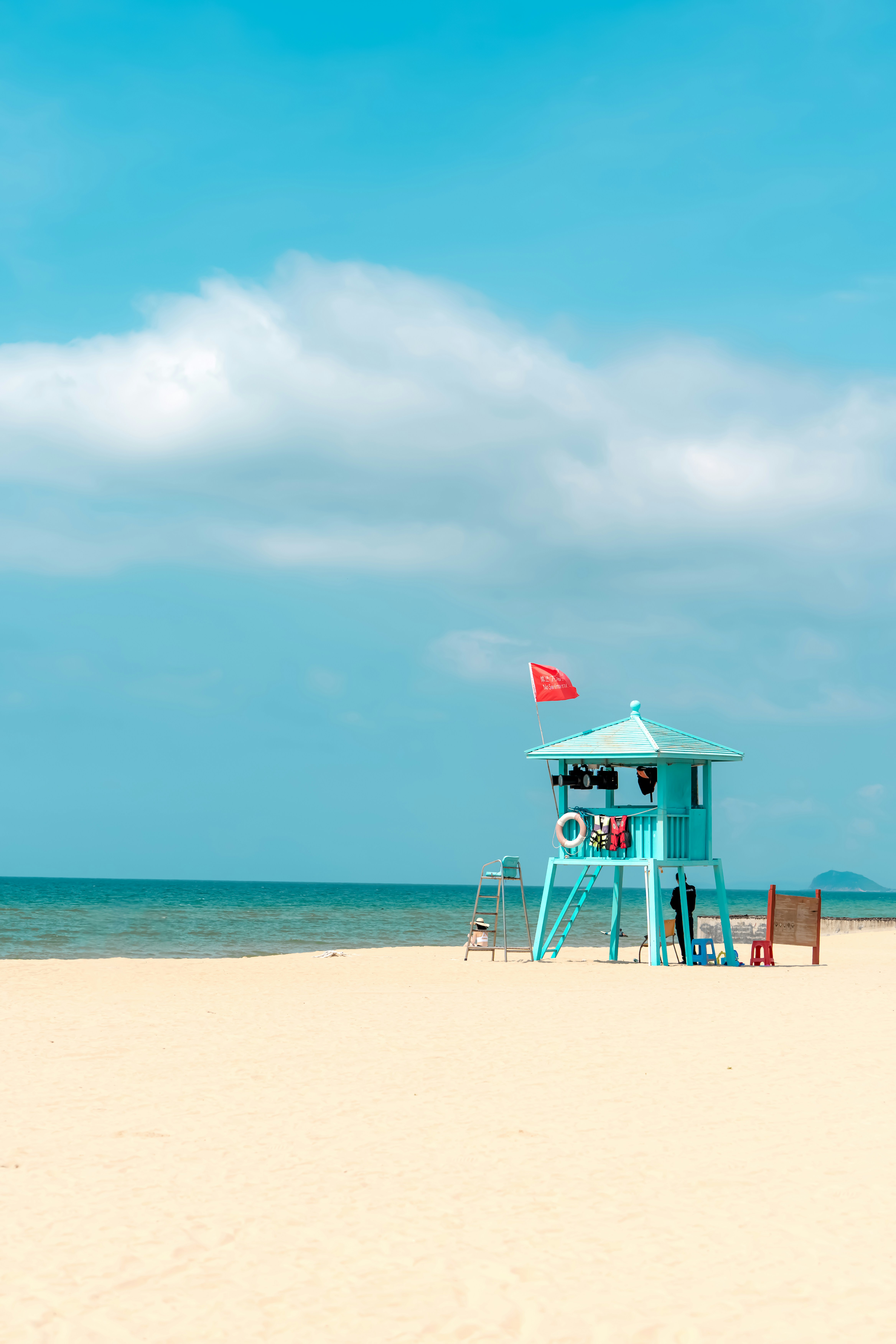 A lifeguard stand on the beach with a lifeguard flag photo – Free ...