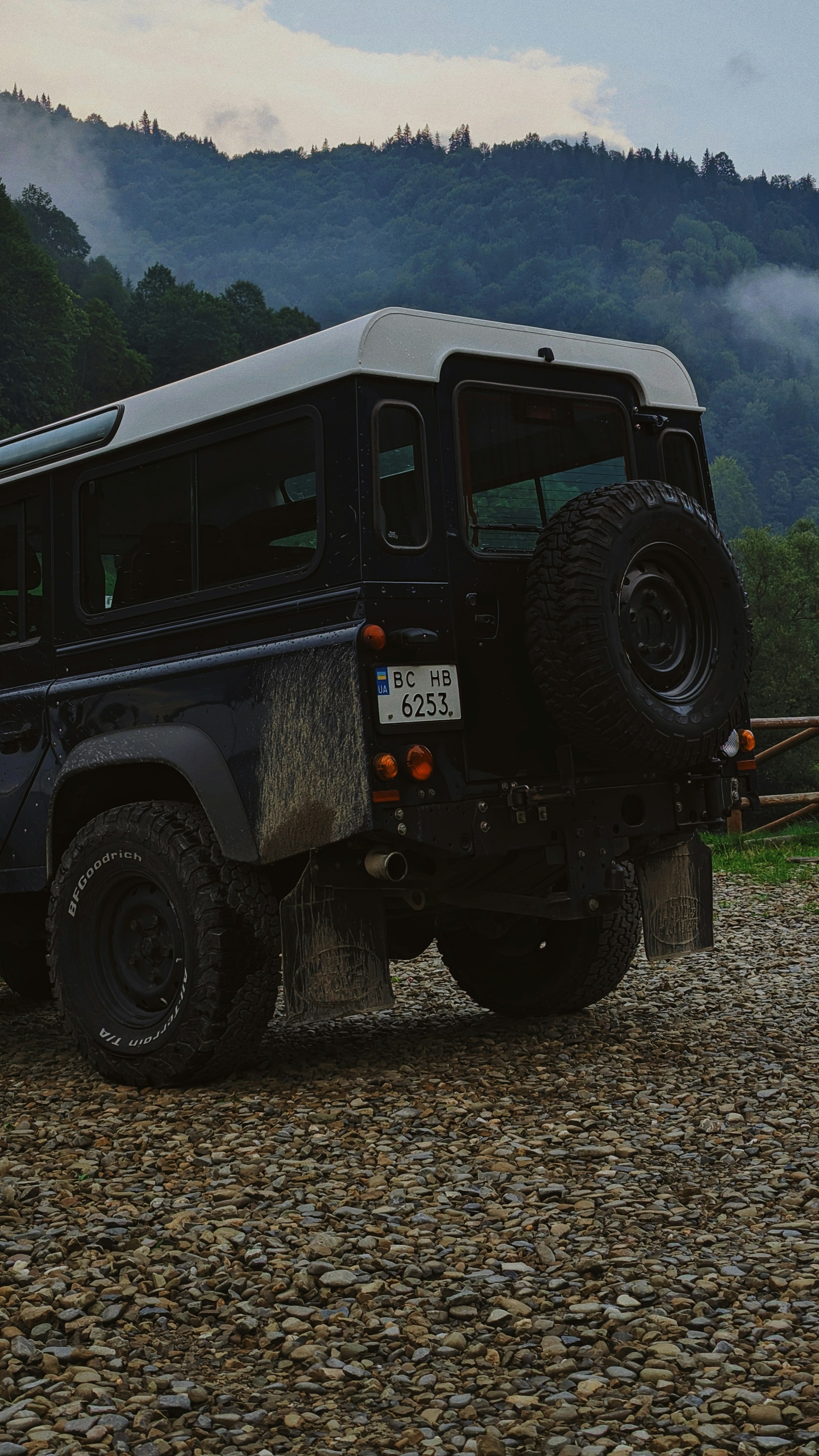 Rugged Defender on a Pebble Trail Beneath a Misty Alpine Sky