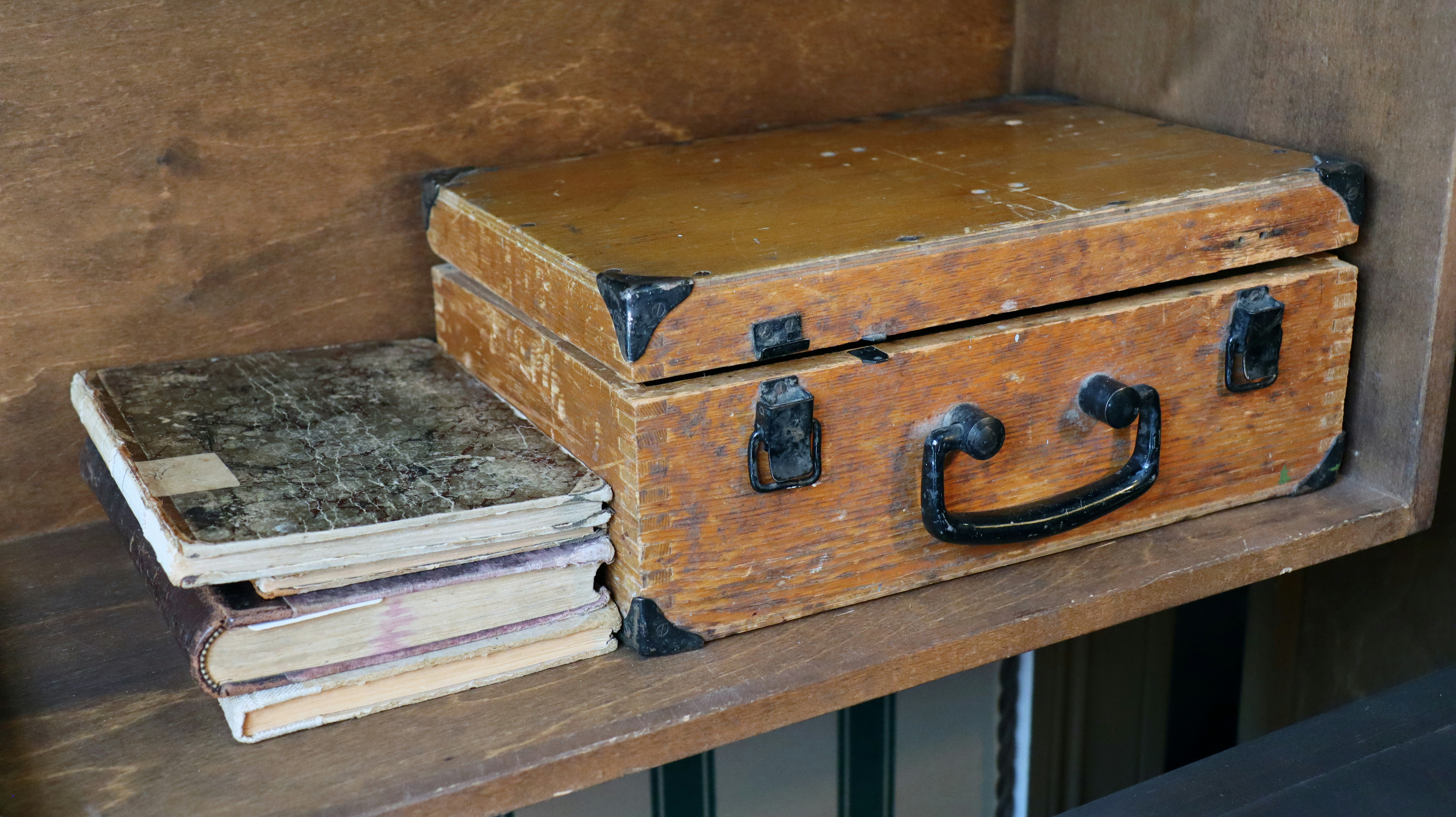 Dusty Keepsakes: A Wooden Briefcase Resting Among Weathered Notebooks