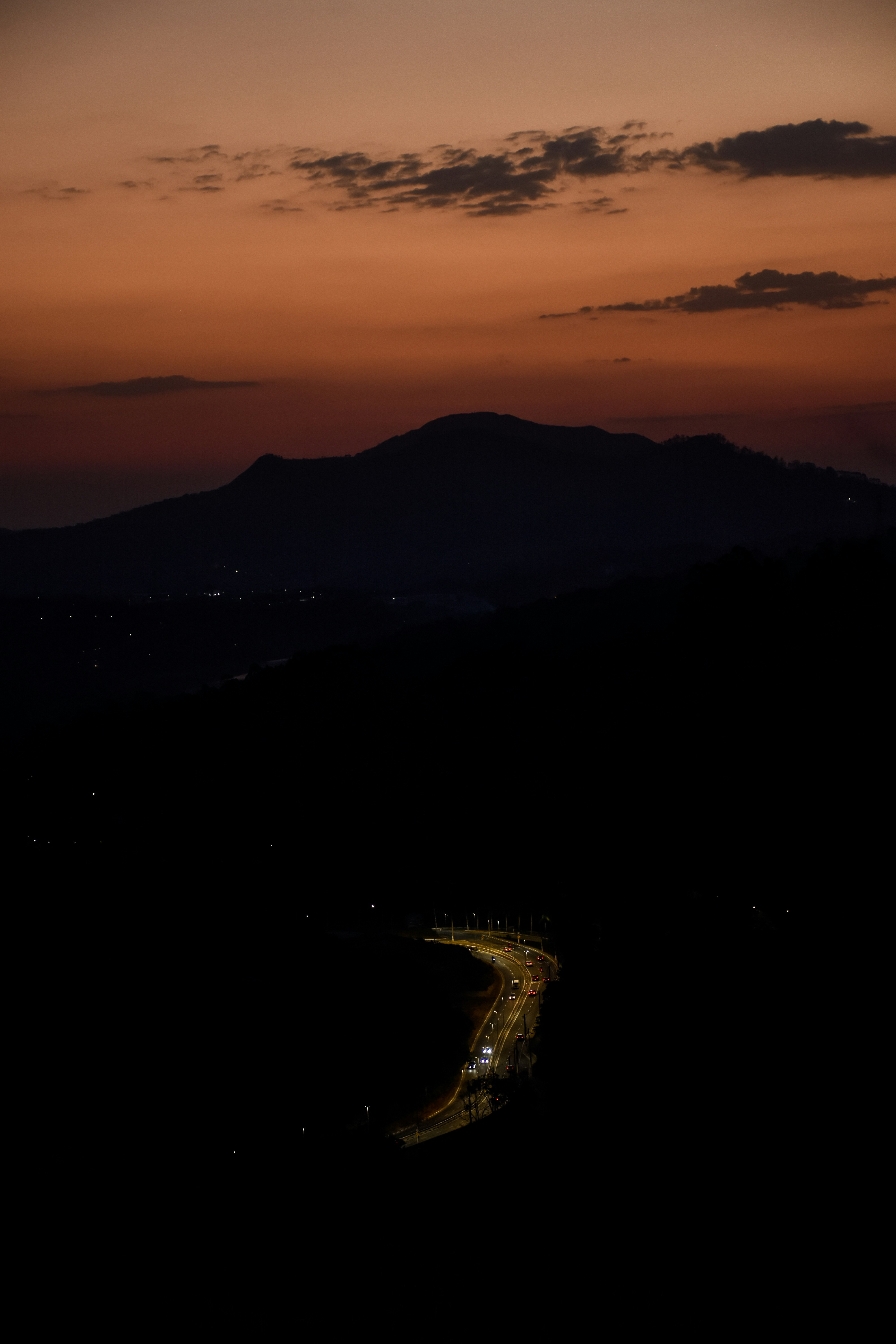 Headlights Carve a Winding Vein Through Nightfall Ridge