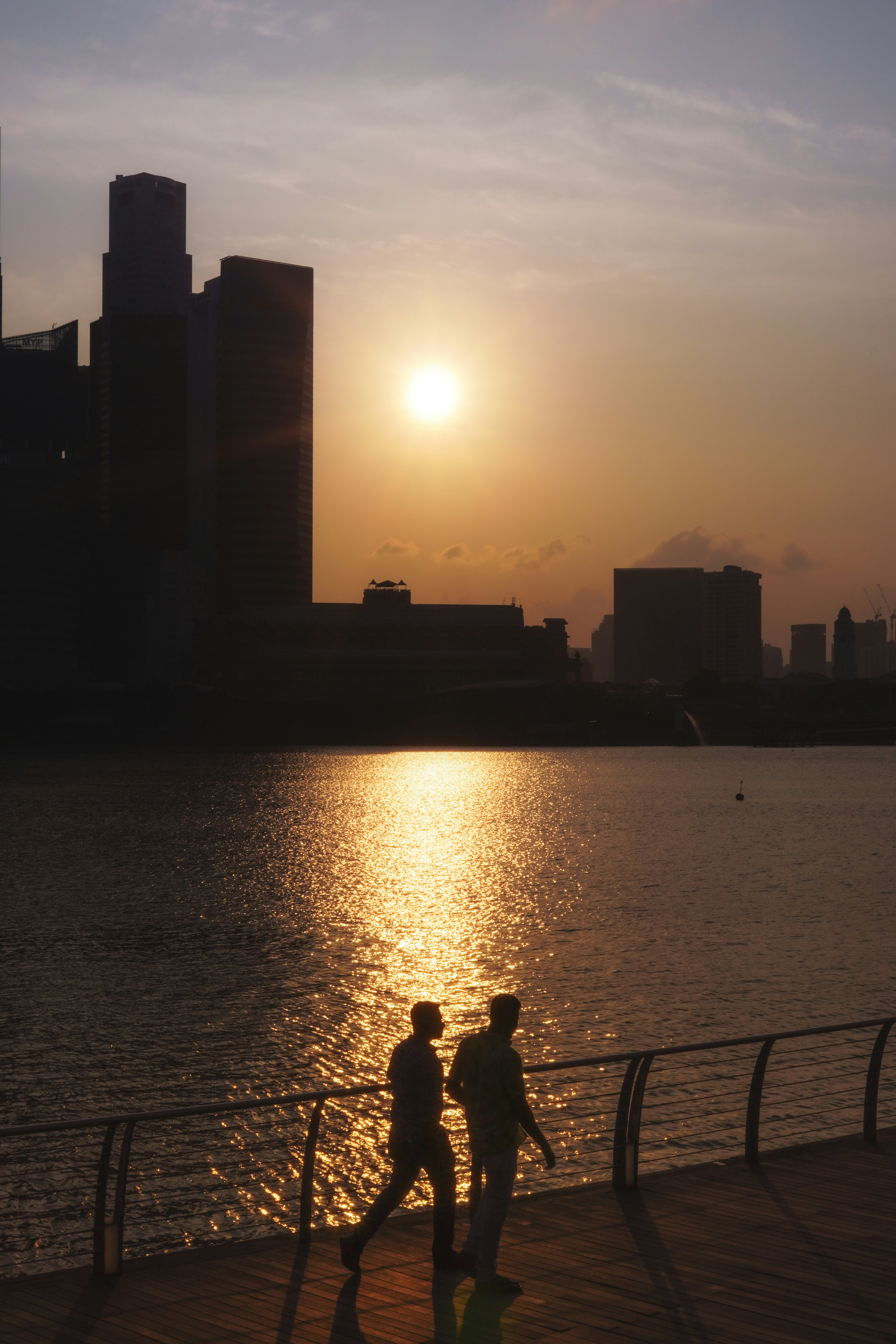 A couple of people that are walking by some water photo – Free Sunset ...