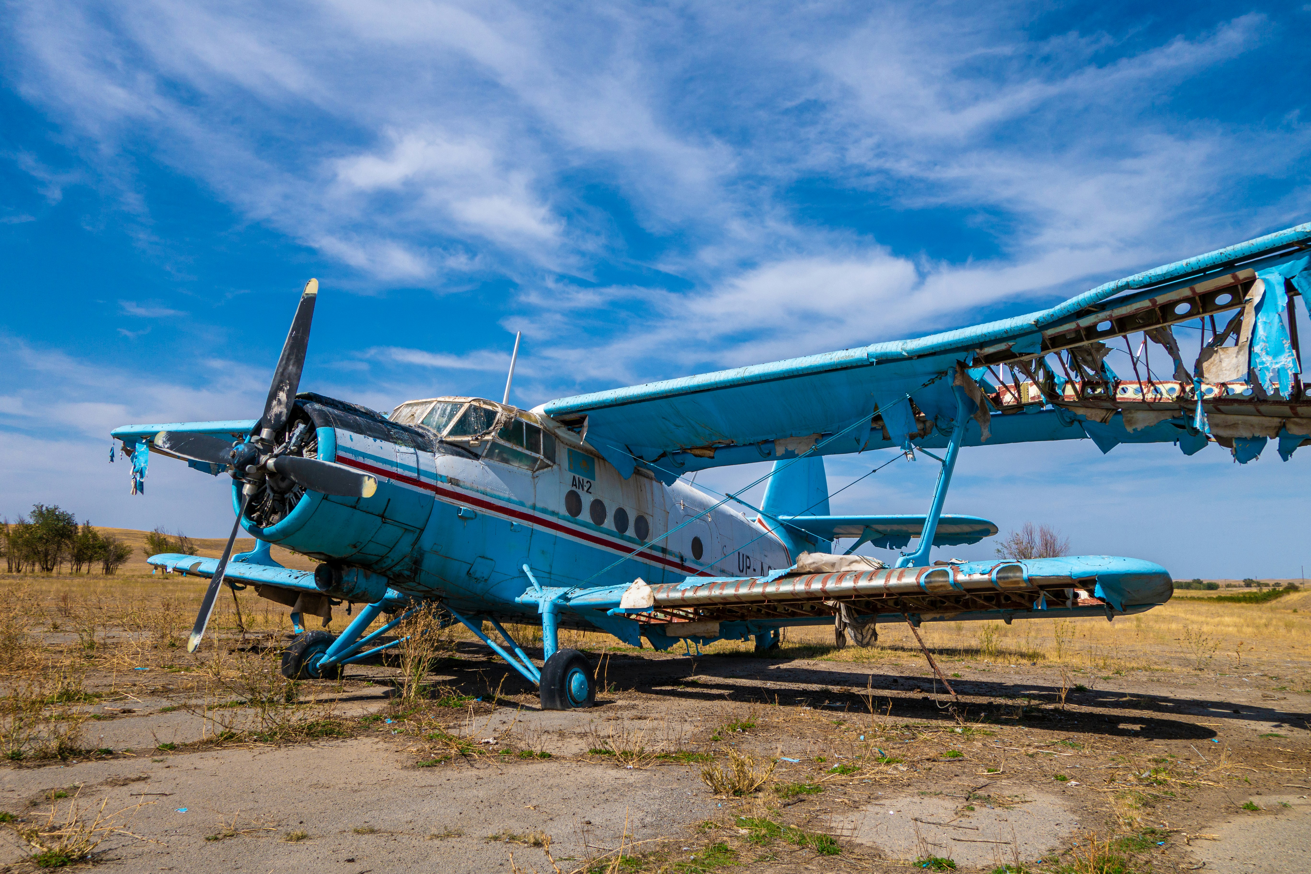 Azure Wreck in the Dust: A Sunlit Seaplane on a Quiet Field