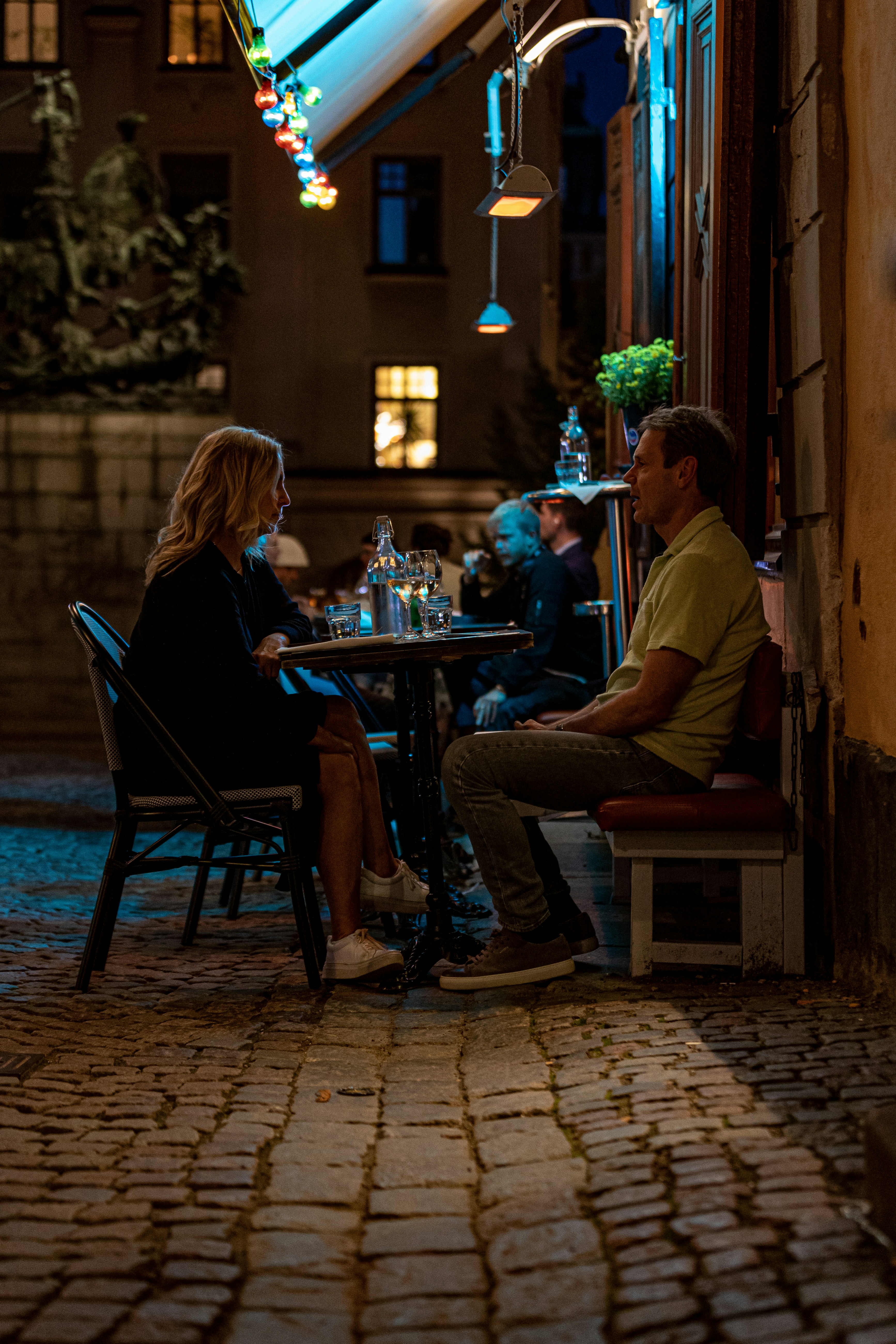 A couple enjoying the evening at a wine bar in Stockholm’s Gamla Stan. | a man and a woman sitting at a table in a restaurant