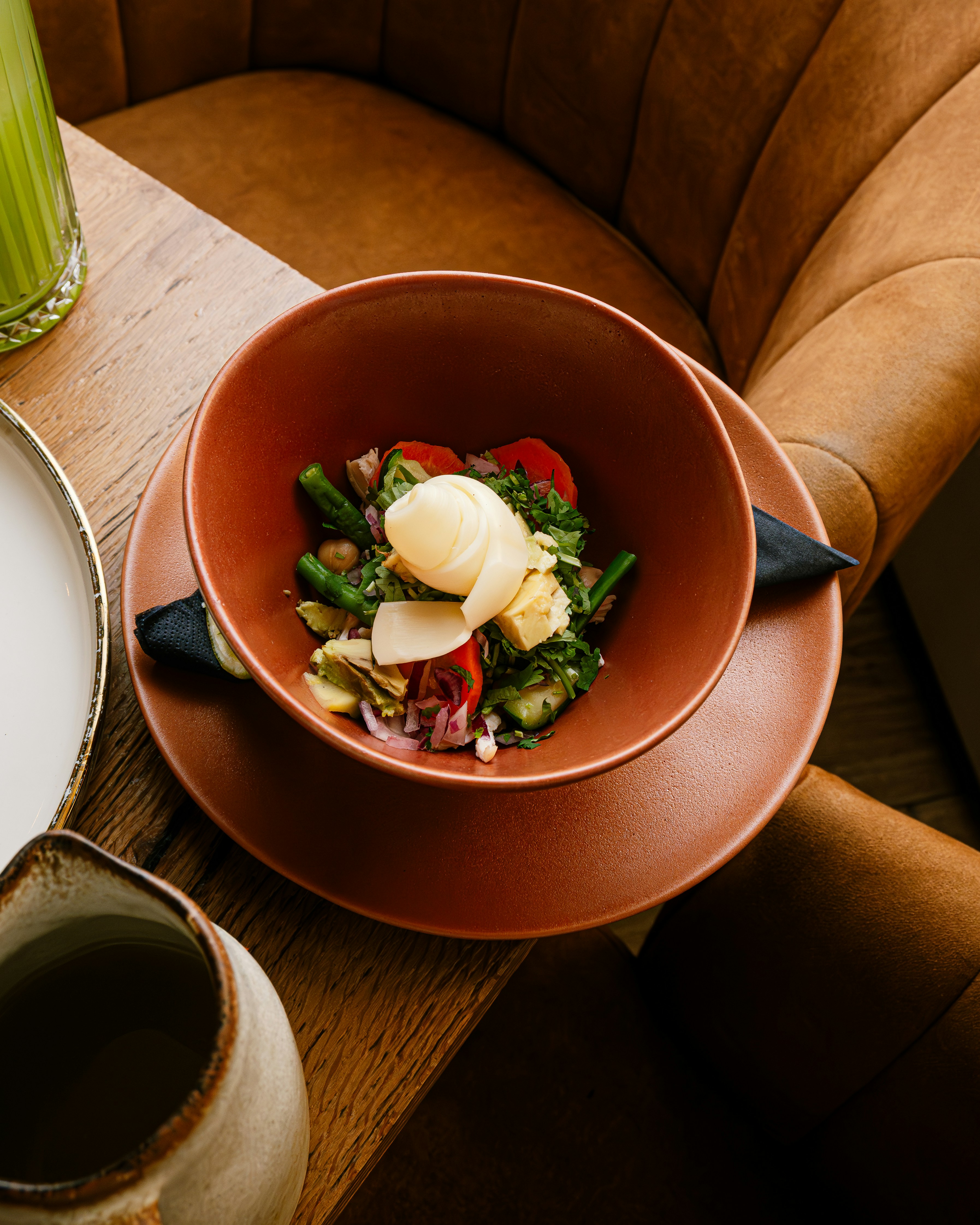Terracotta Bowl of Greens: Cheese Shavings and Color on a Cozy Café Table