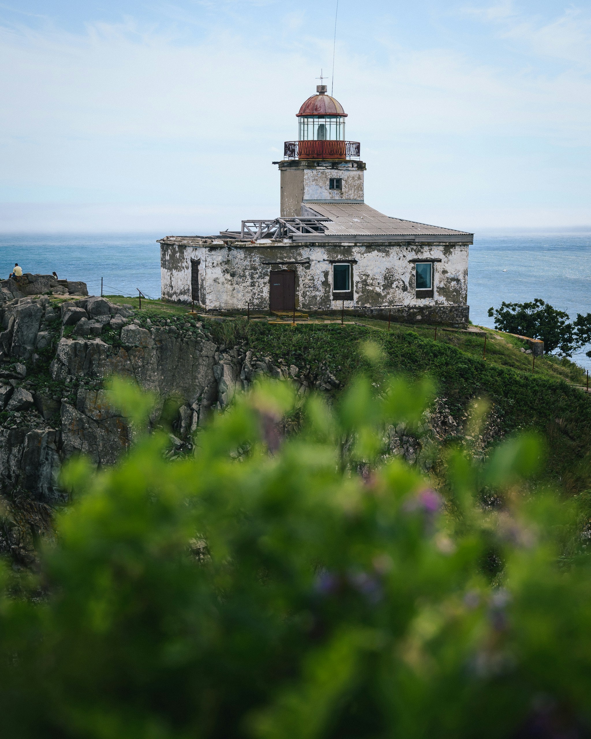 A lighthouse on top of a cliff overlooking the ocean photo – Free ...