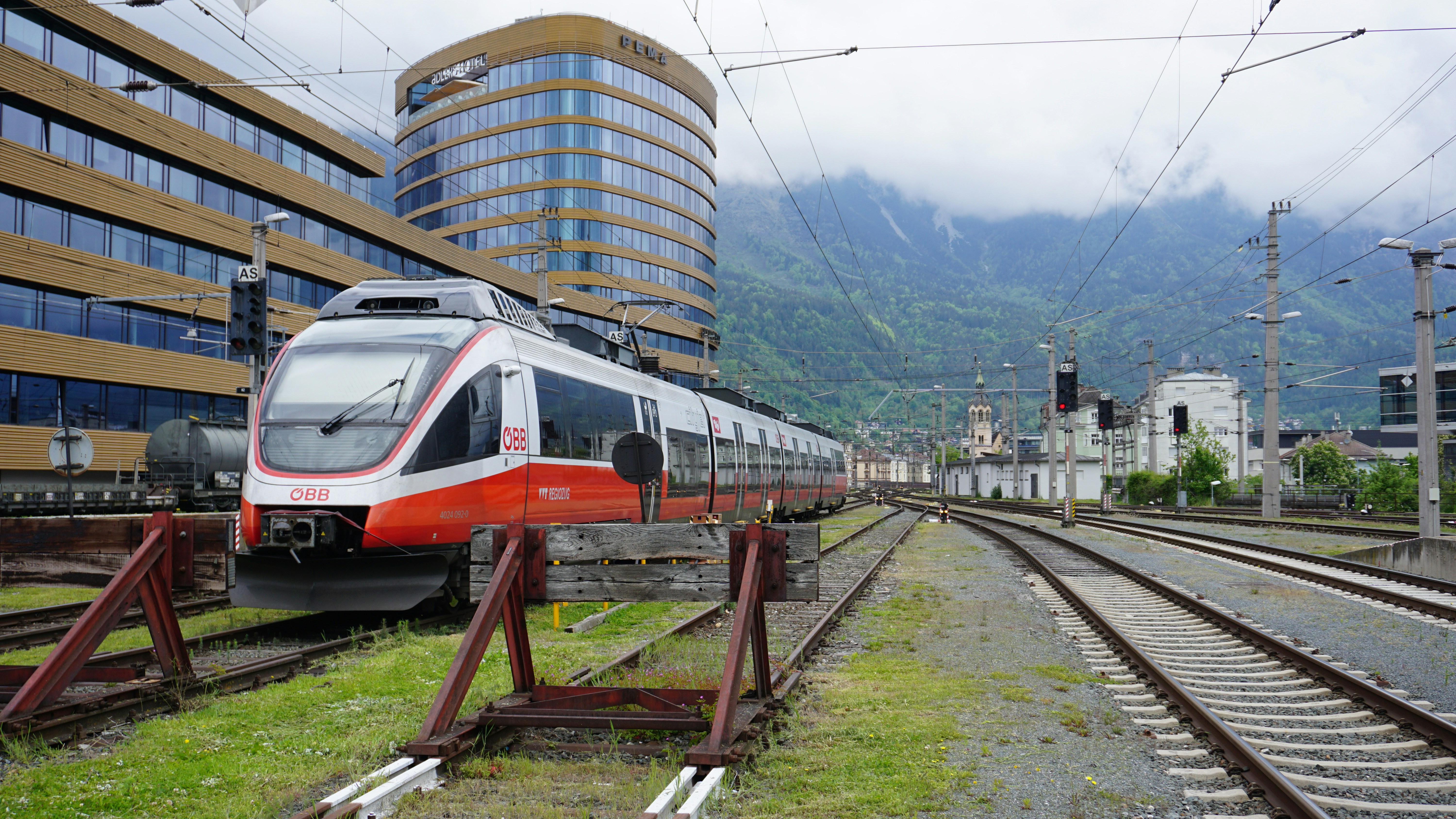 Crimson Front, Alpine Backdrop: A Commuter Train at a Mountain-Urban Junction