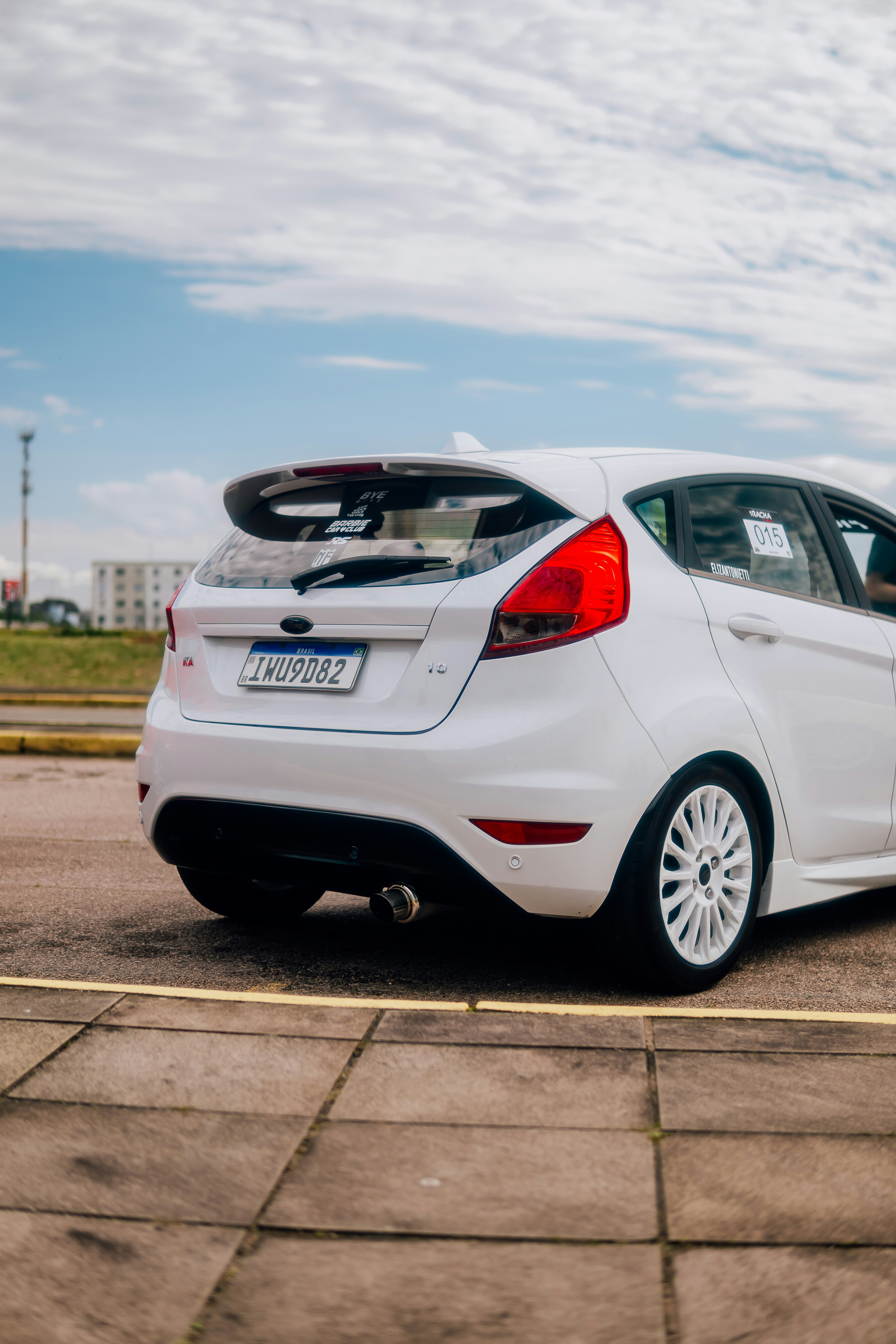 White hatchback with rear spoiler parked on a paved lot