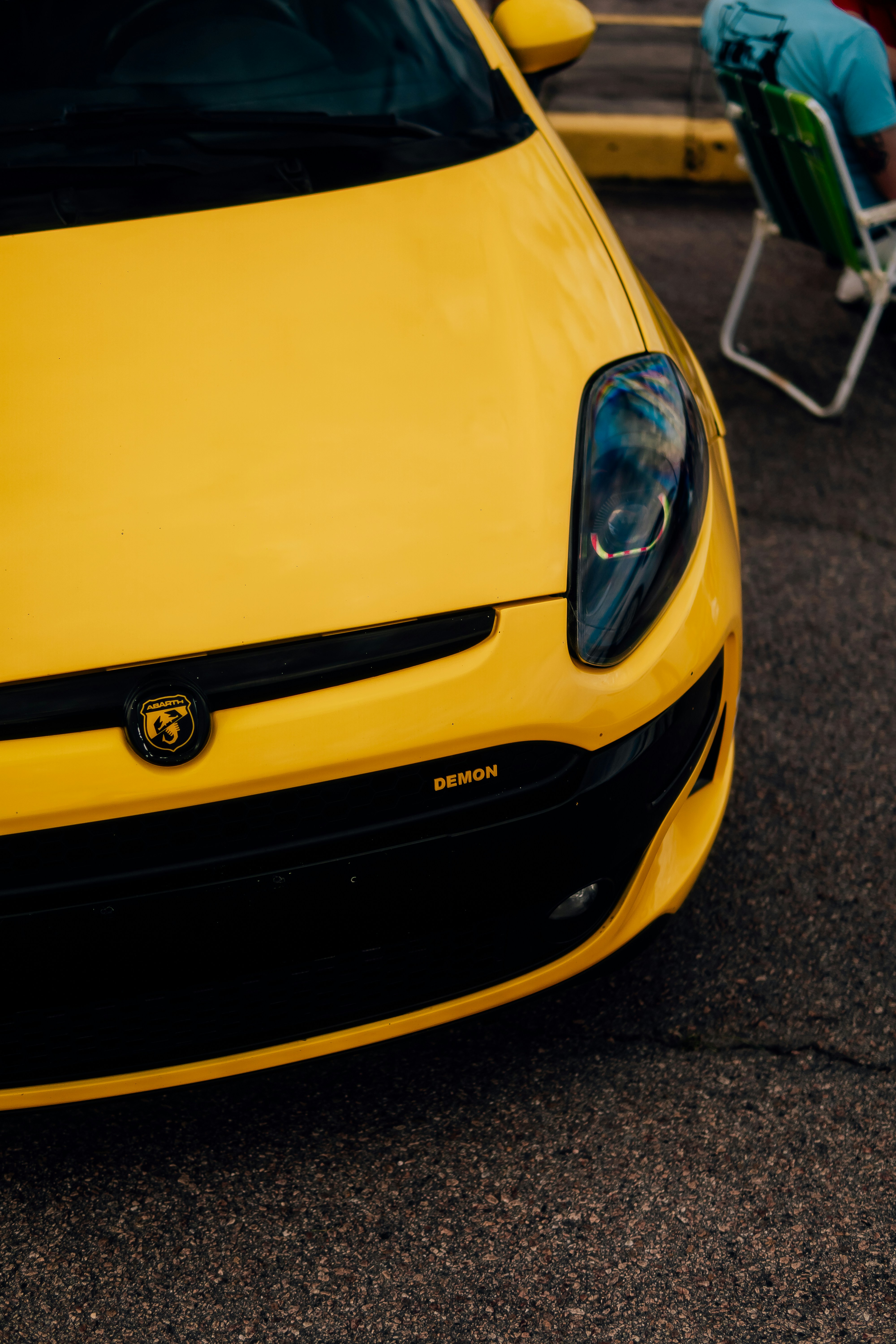 Front-Frame Demon: A Close-Up of a Vivid Yellow Car's Emblem and Headlight