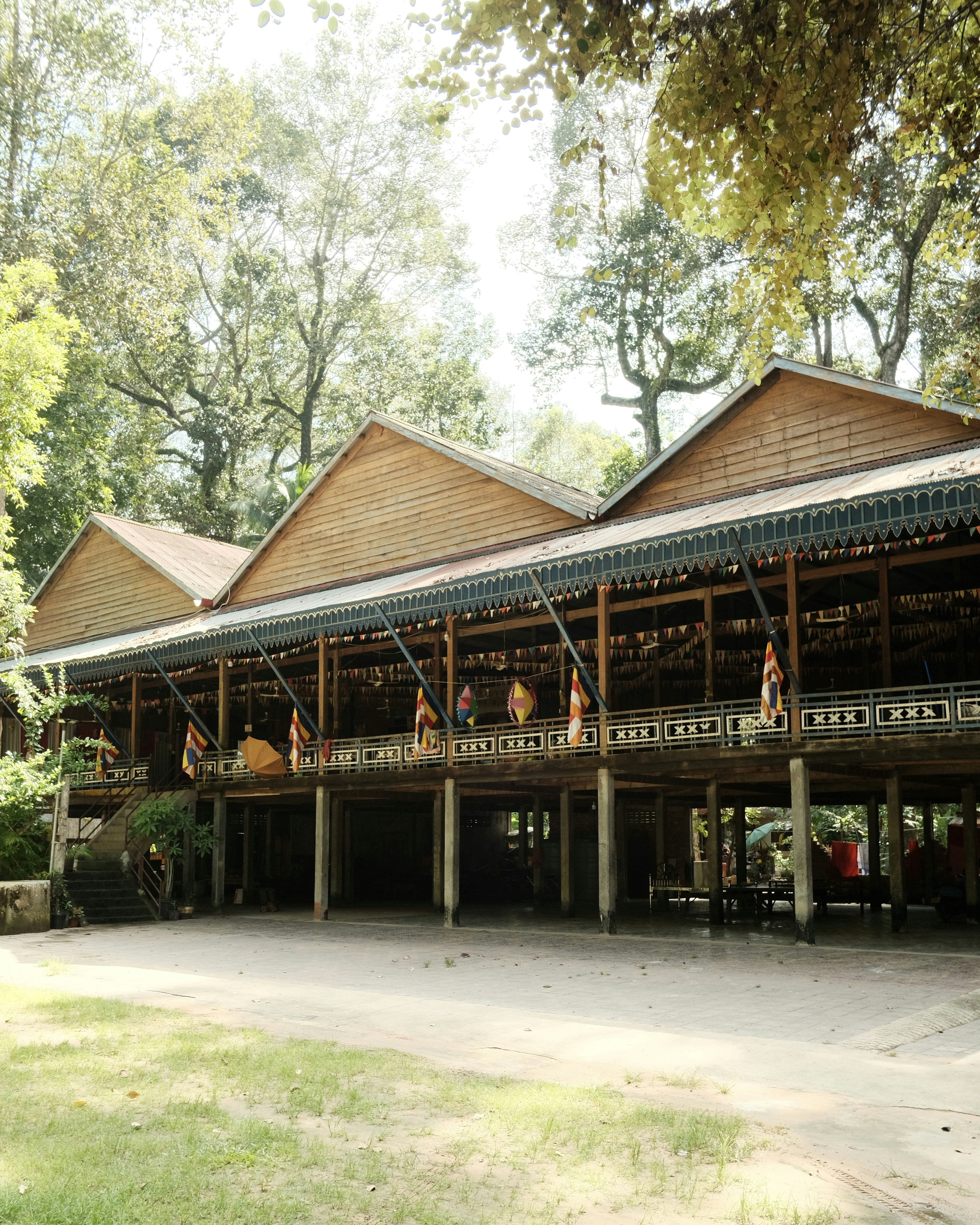 Sunlit Row of Stilted Wooden Pavilions Framing a Leafy Corridor