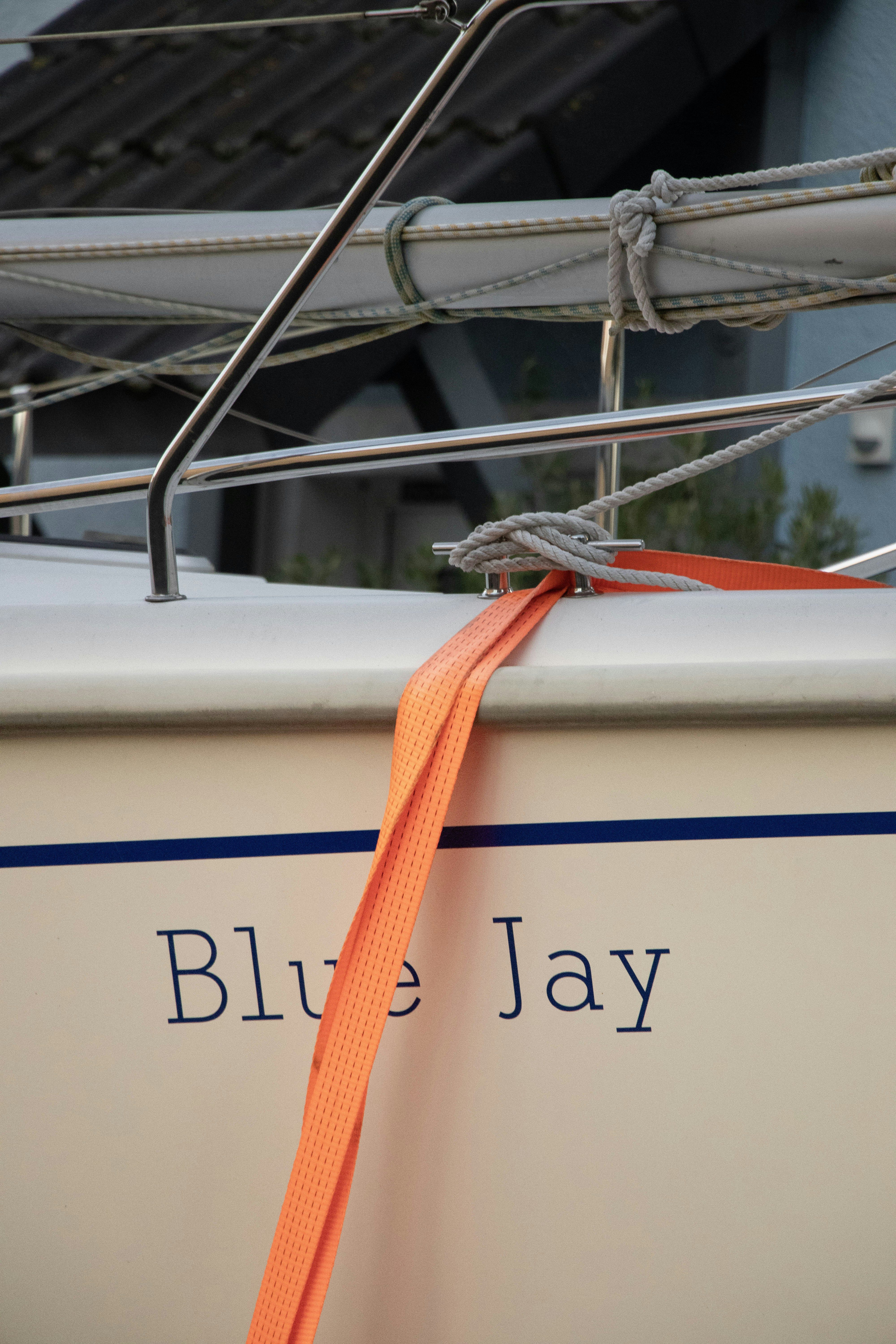 Orange Strap Draped Over the Hull of Blue Jay: A Sailboat Close-Up