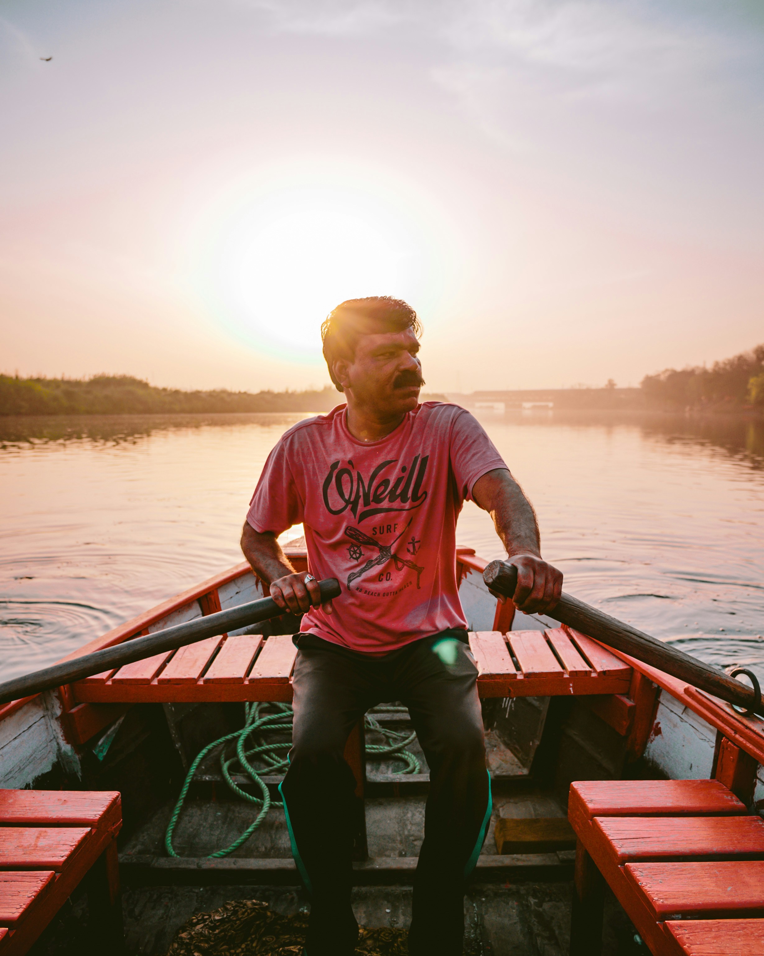 Sunlit Oarsman: Focused Gaze Amid River Calm