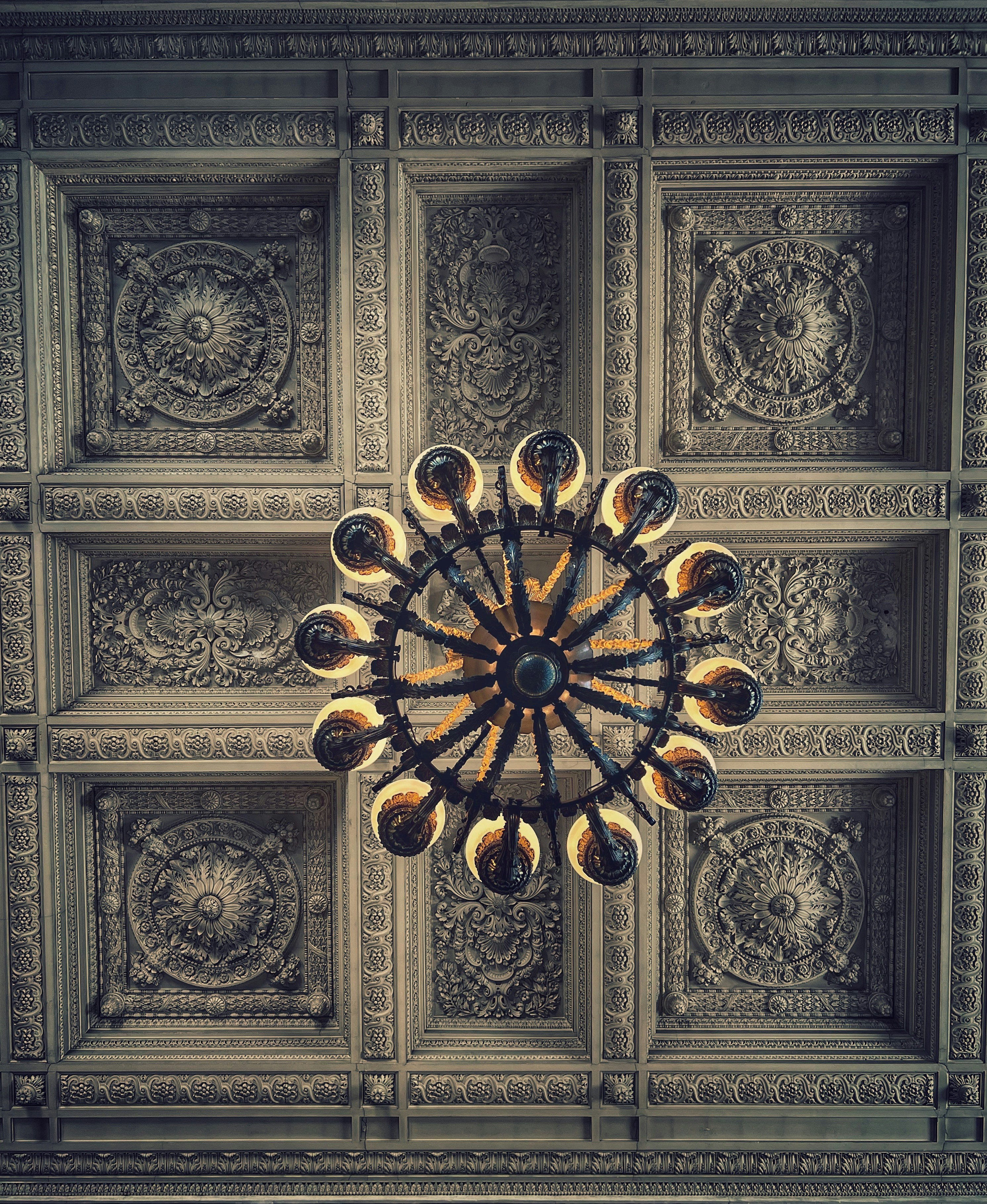 Ornate Chandelier Crowned by a Geometric Carved Ceiling