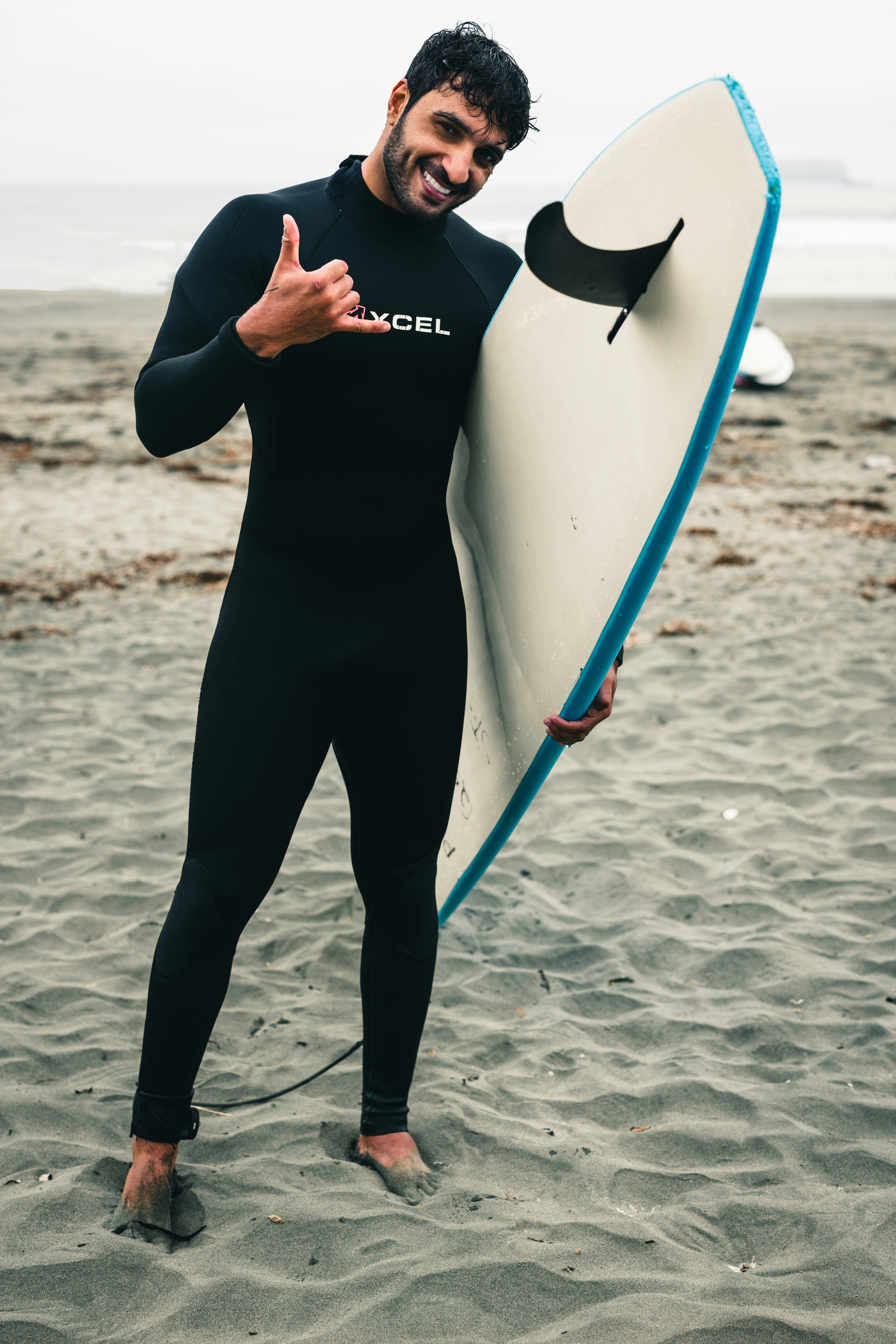 Shaka on Sand: A Surfer's Beach Portrait with a Wave-Ready Board