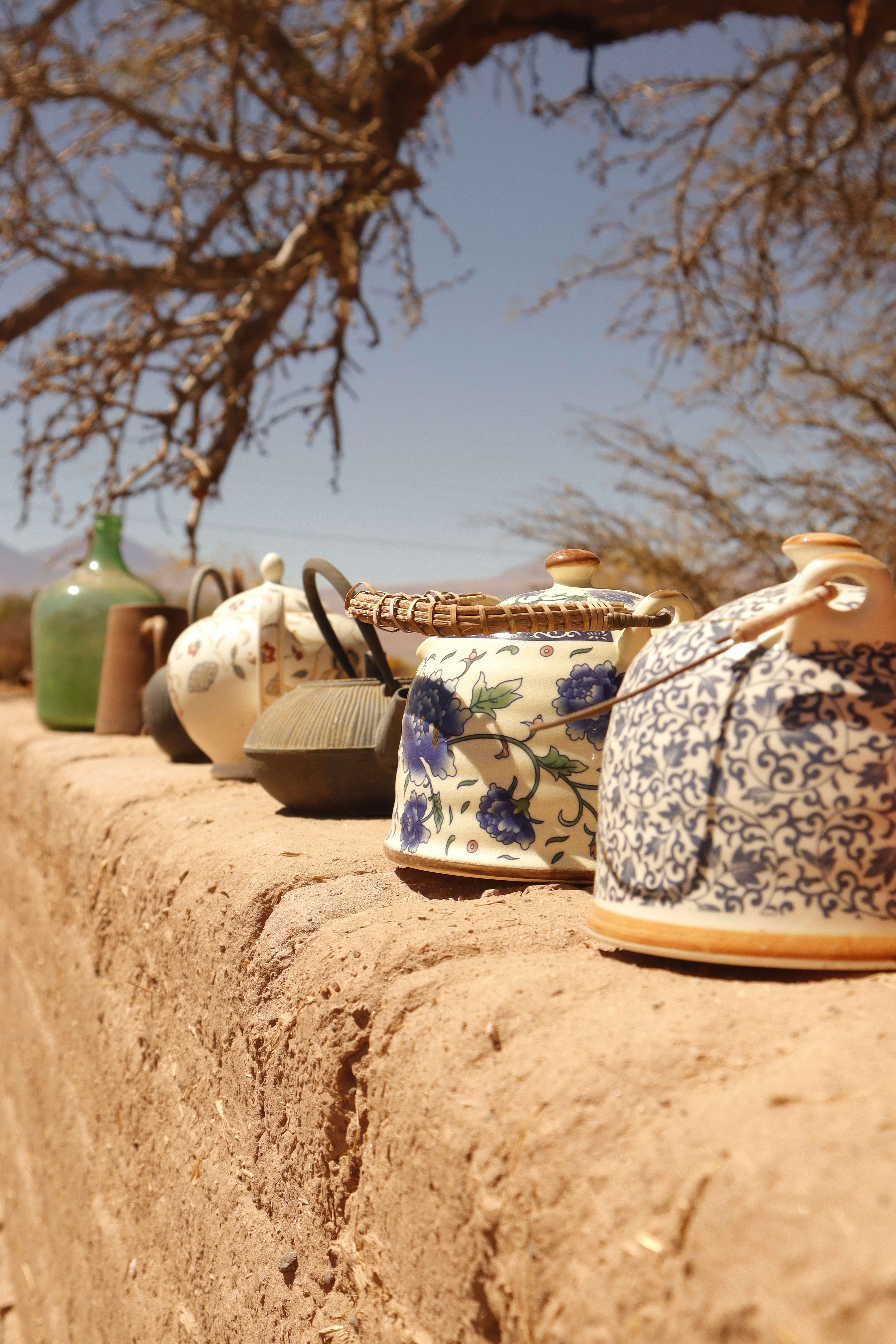 Ceramic Pitchers Lineup on a Sunlit Earthen Wall