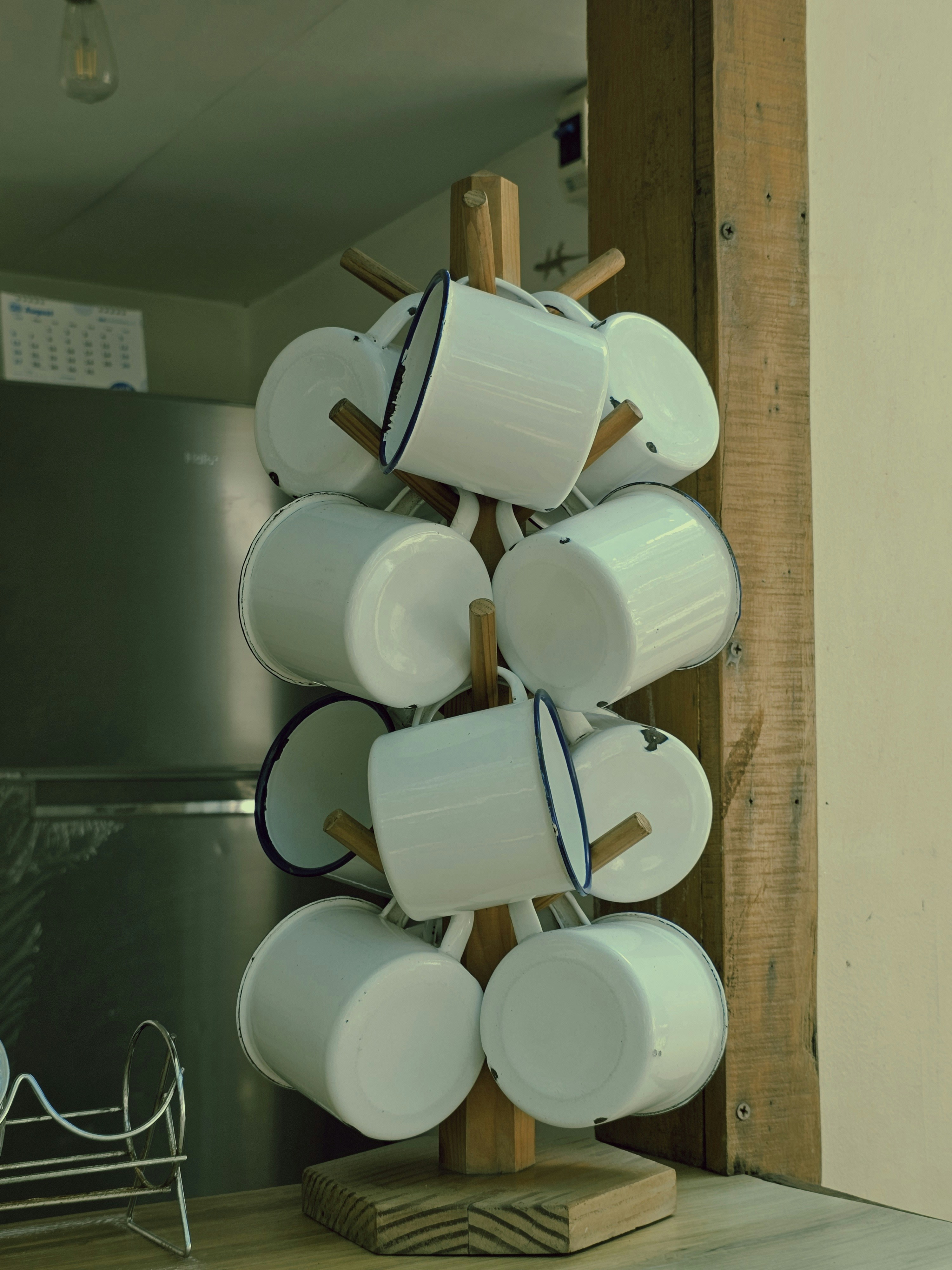 Stacked white mugs on a wooden rack in a cozy kitchen corner