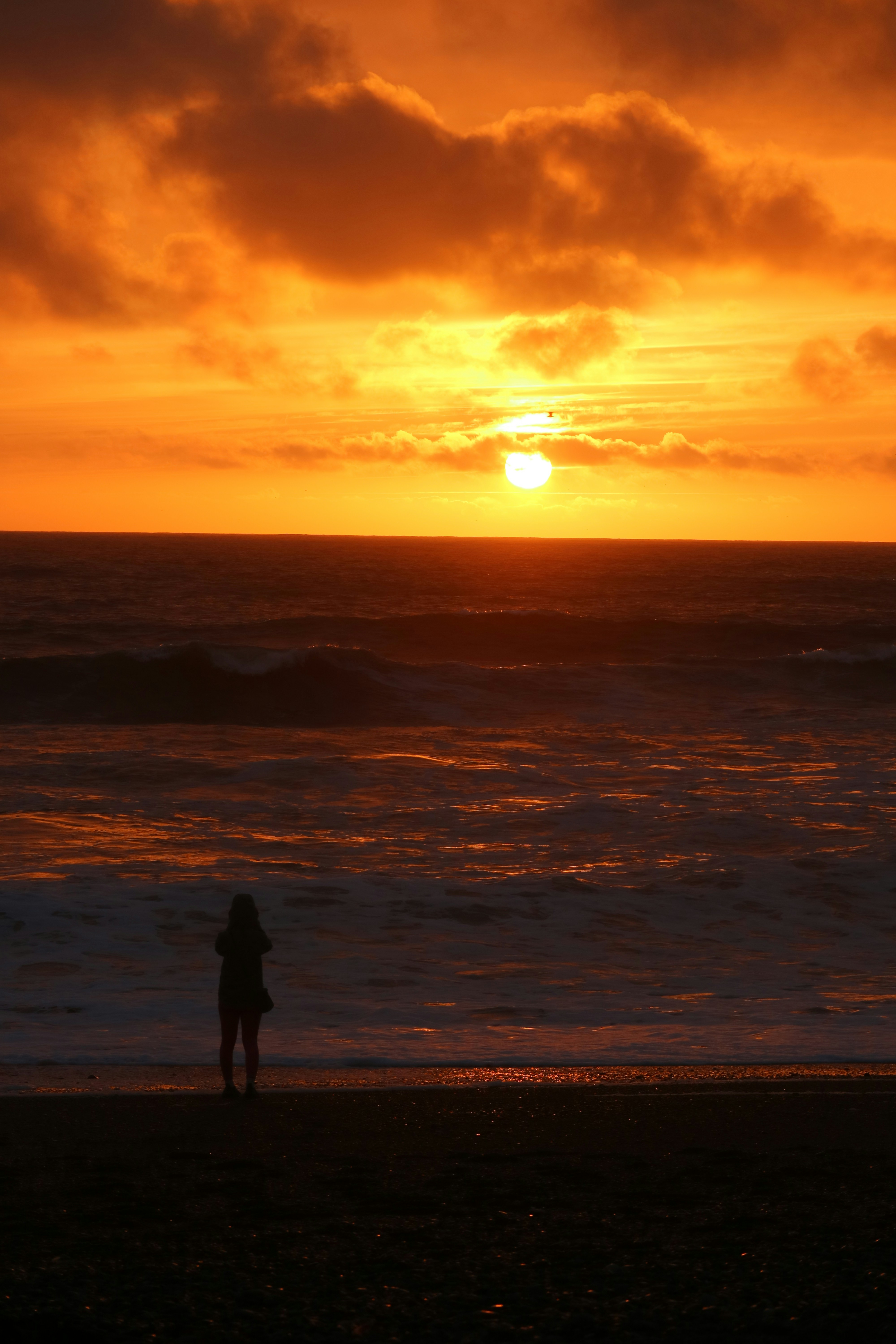 A person standing on a beach at sunset photo – Free Beach Image on Unsplash