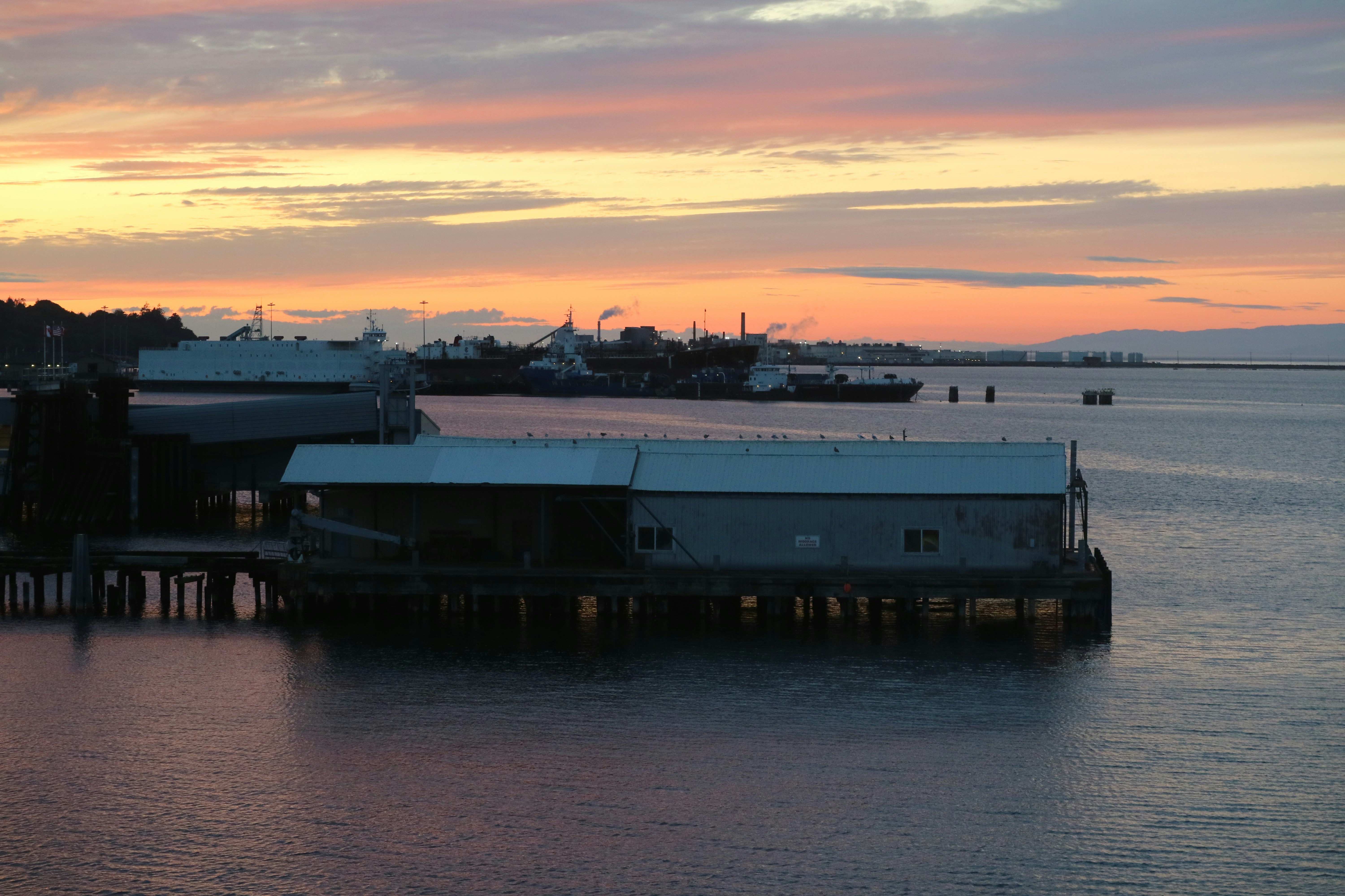 Building on a dock silhouetted against a vibrant sunset over calm waters.