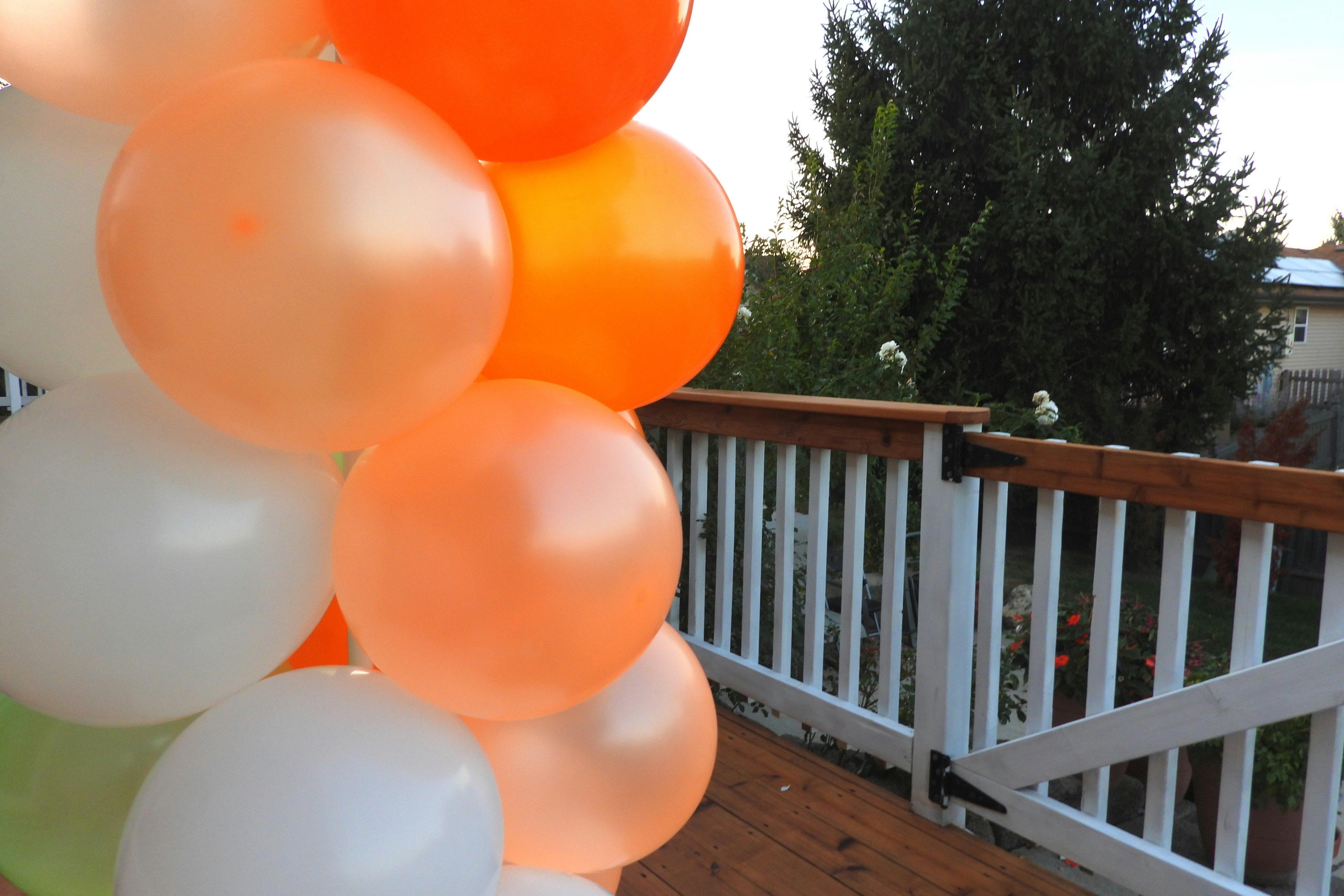 a bunch of orange and white balloons on a porch