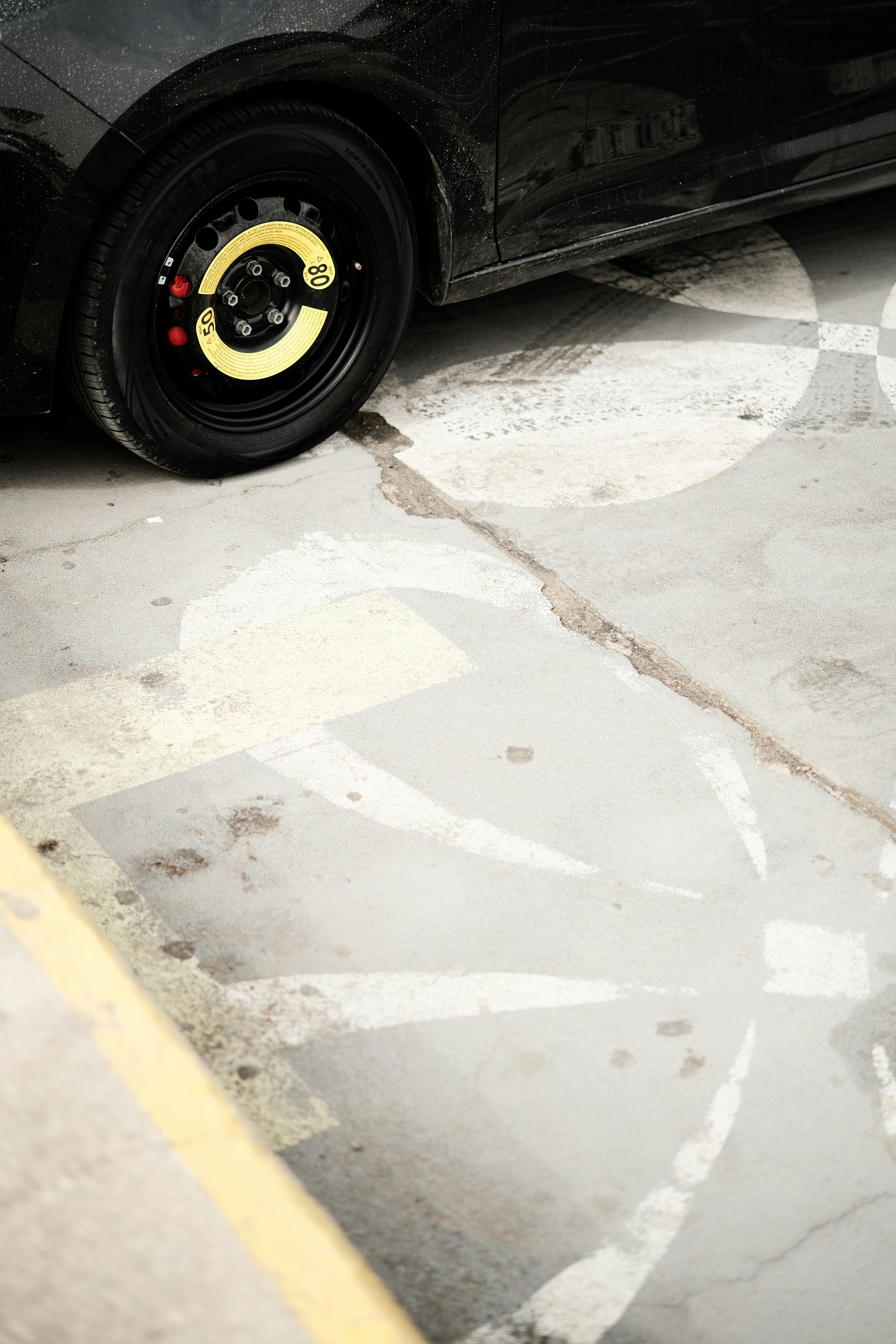 Yellow-Rimmed Wheel in a Moody Parking-Lot Geometry
