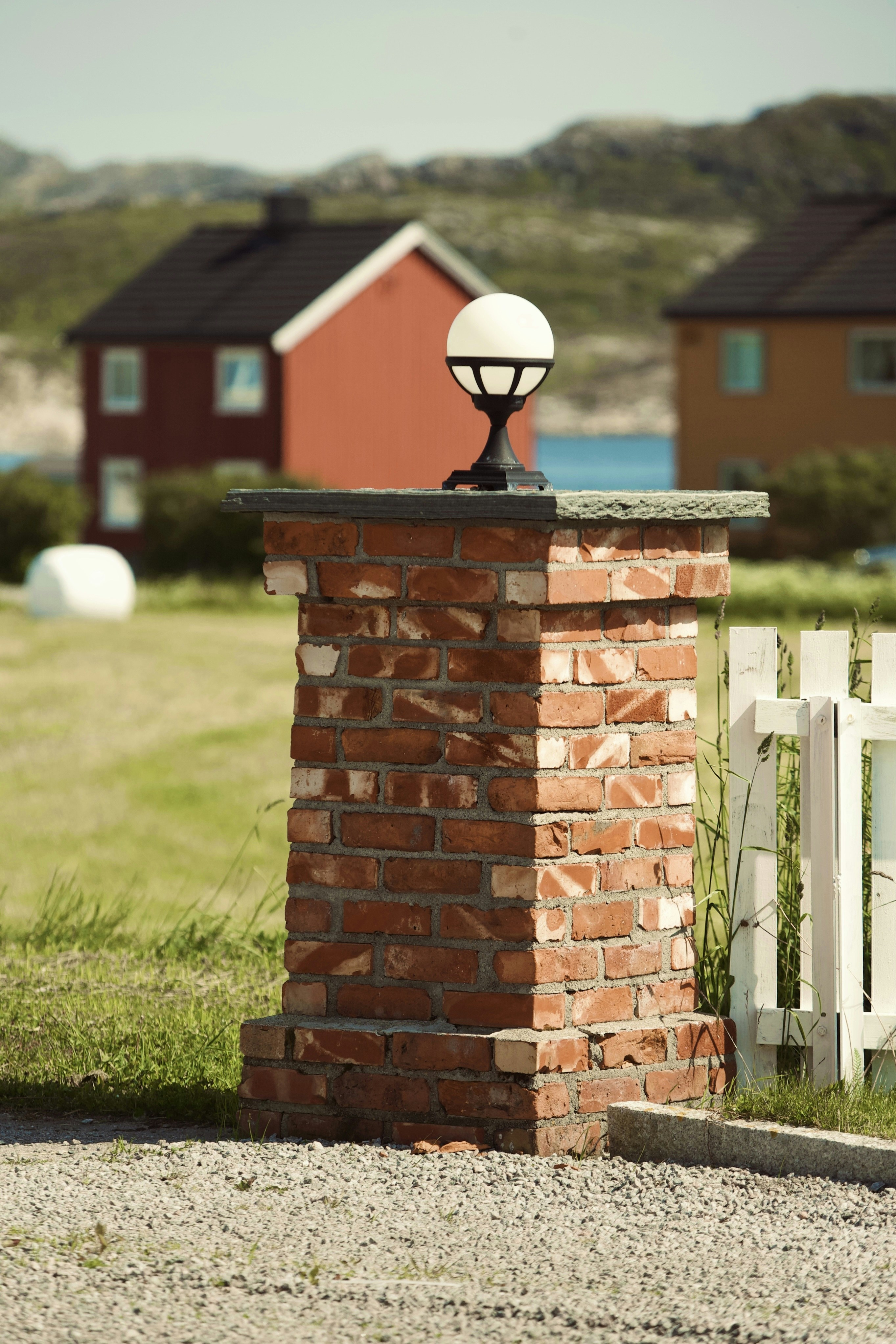 Brick Pillar Lighthouse: A Brickwork Beacon in a Sunlit Coastal Yard