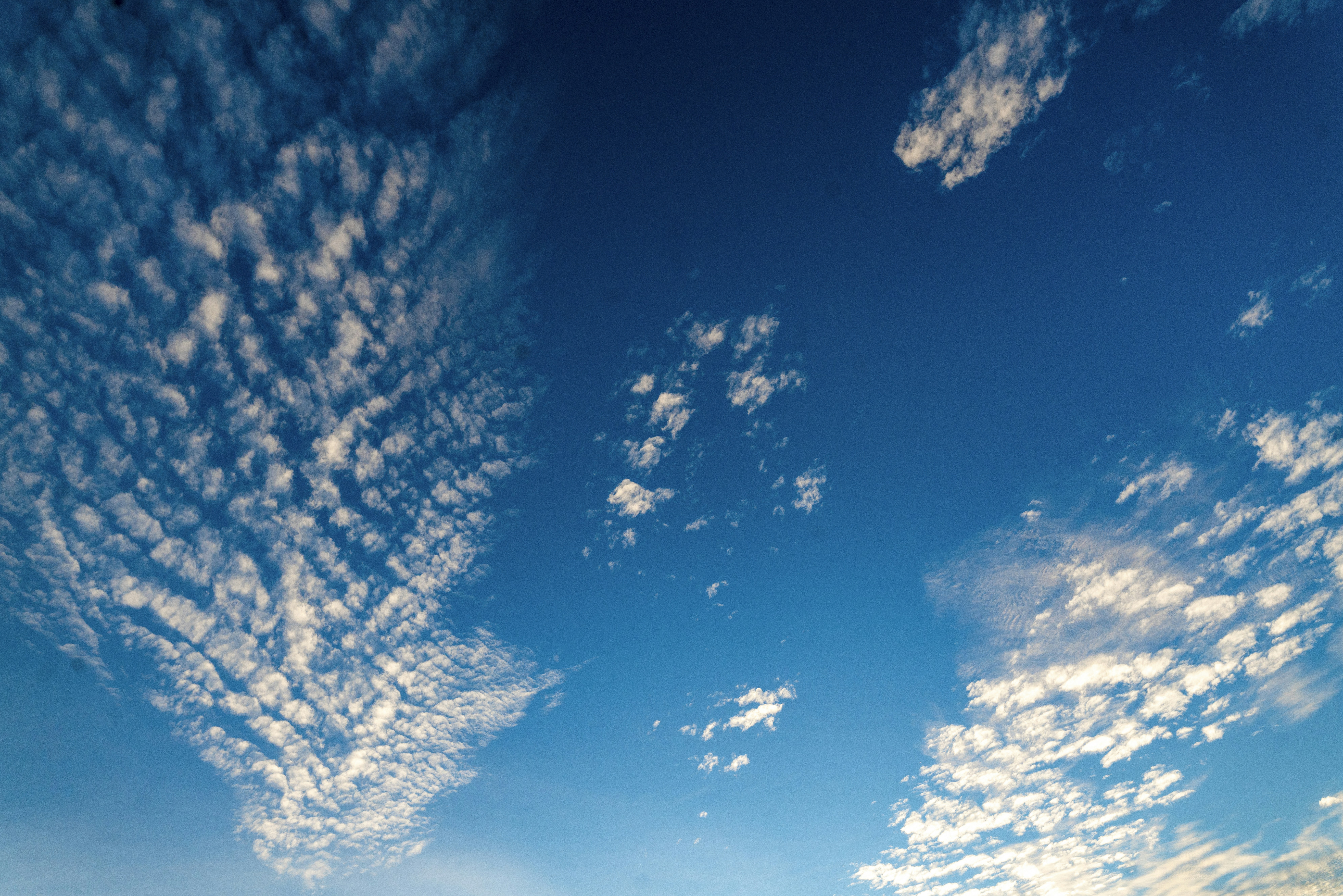 A blue sky with some clouds and a plane in the distance photo – Free ...