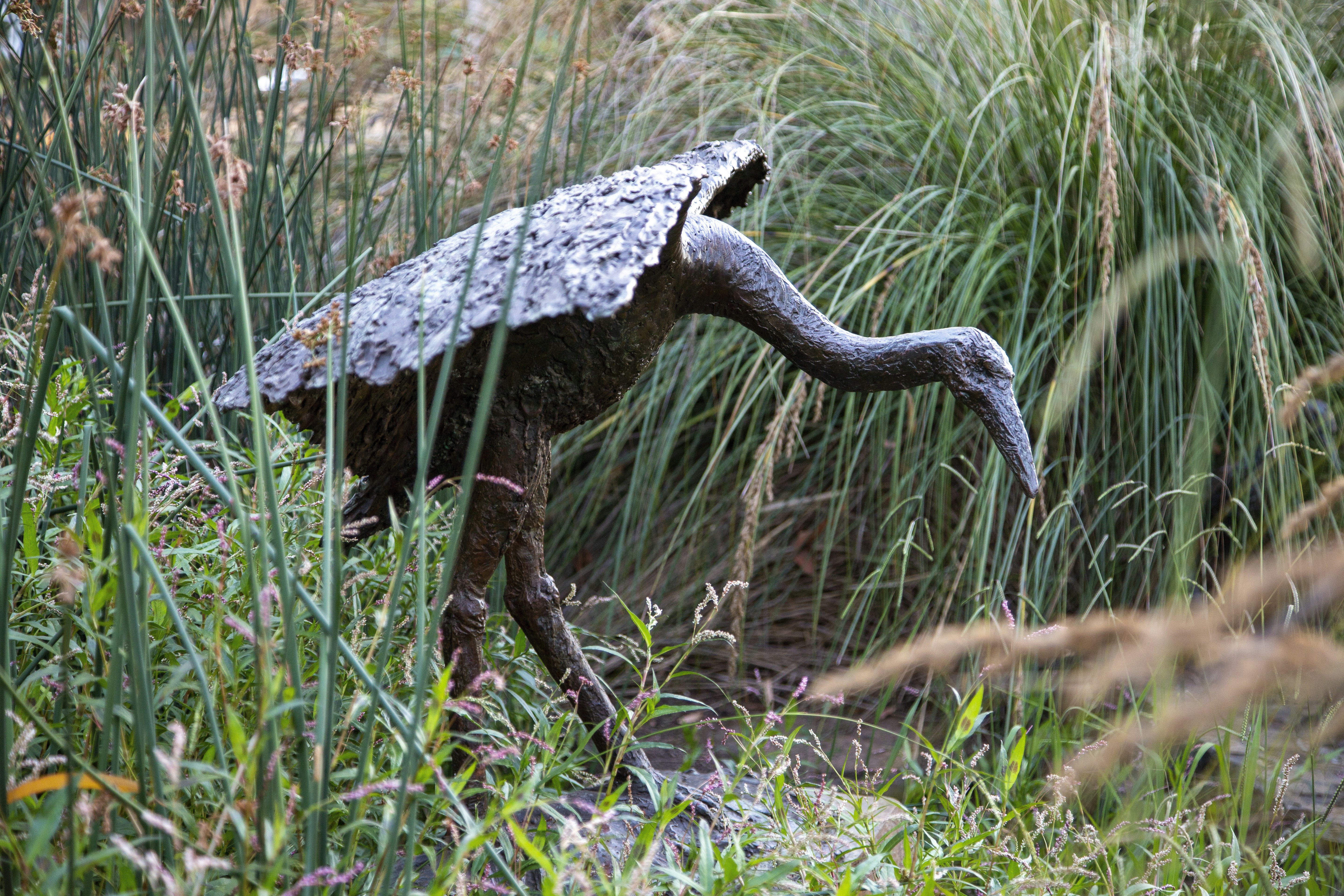 a statue of a snake in a field of tall grass