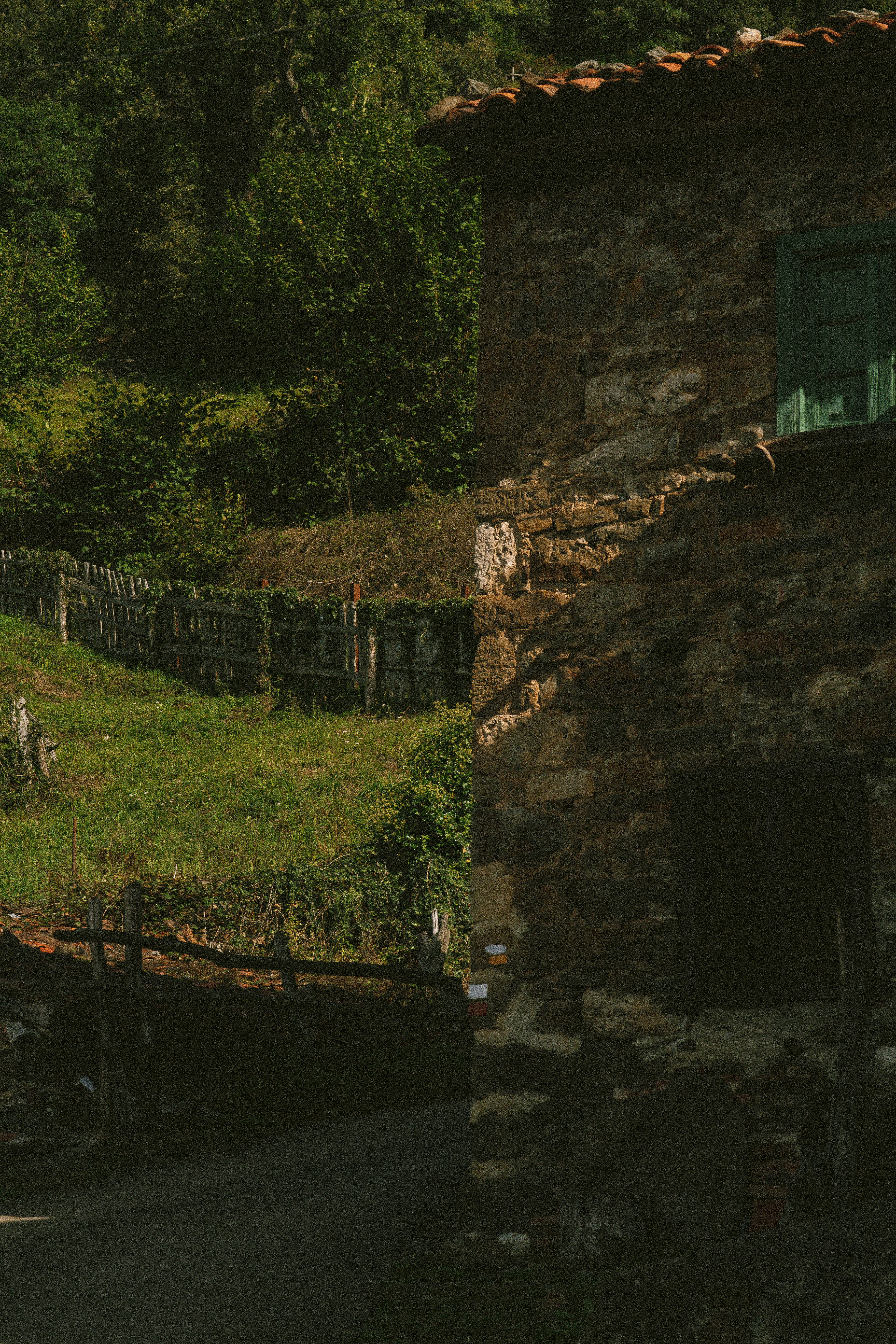 Sunlit stone cottage at the bend of a quiet hillside lane
