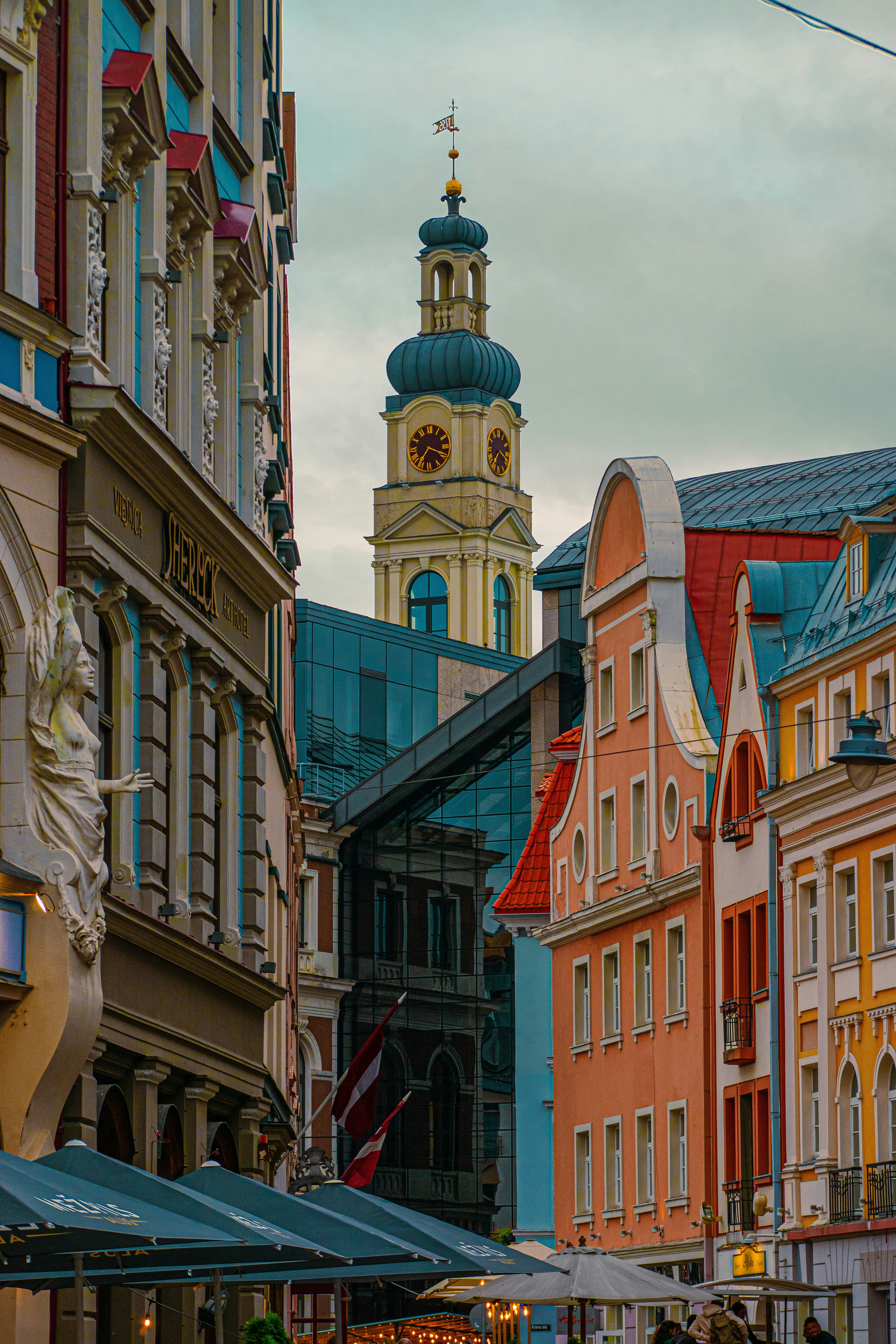 A group of people walking down a street next to tall buildings photo ...