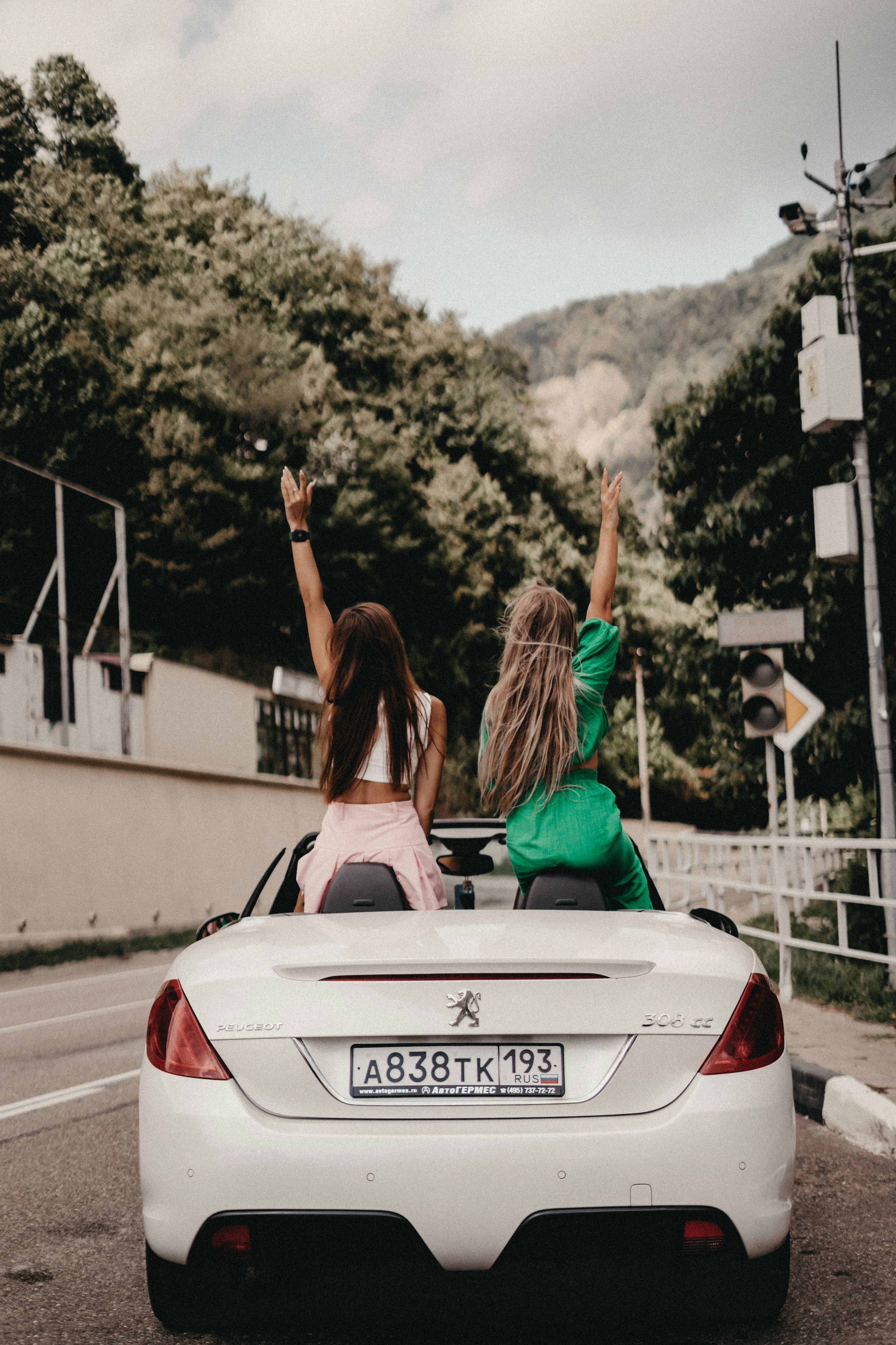 Daylight Road-Trip Anthem: Two Friends Raise Their Hands in a White Convertible