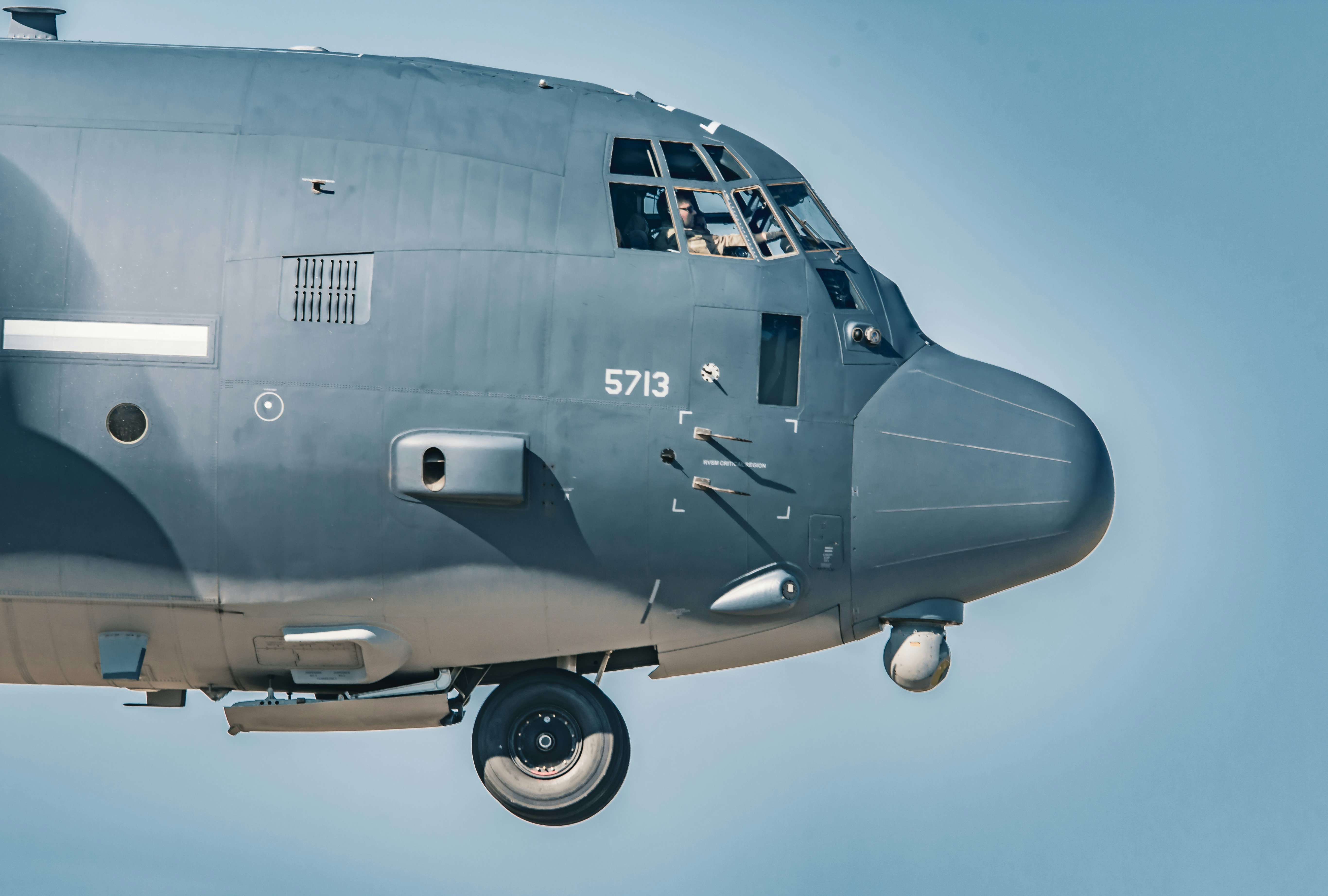 A large military plane flying through a blue sky photo – Free Grey ...