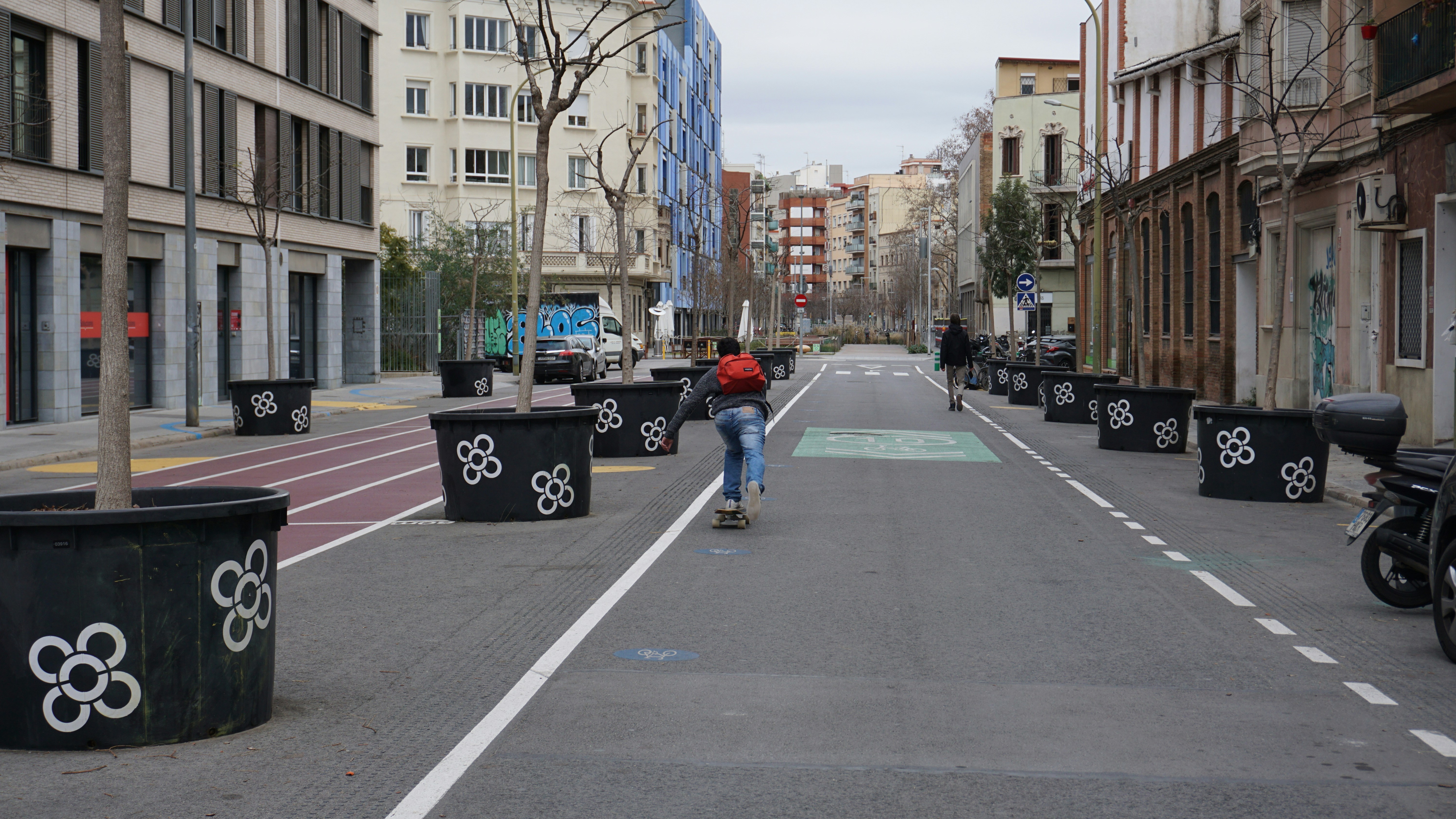 A man riding a skateboard down a street next to tall buildings photo ...