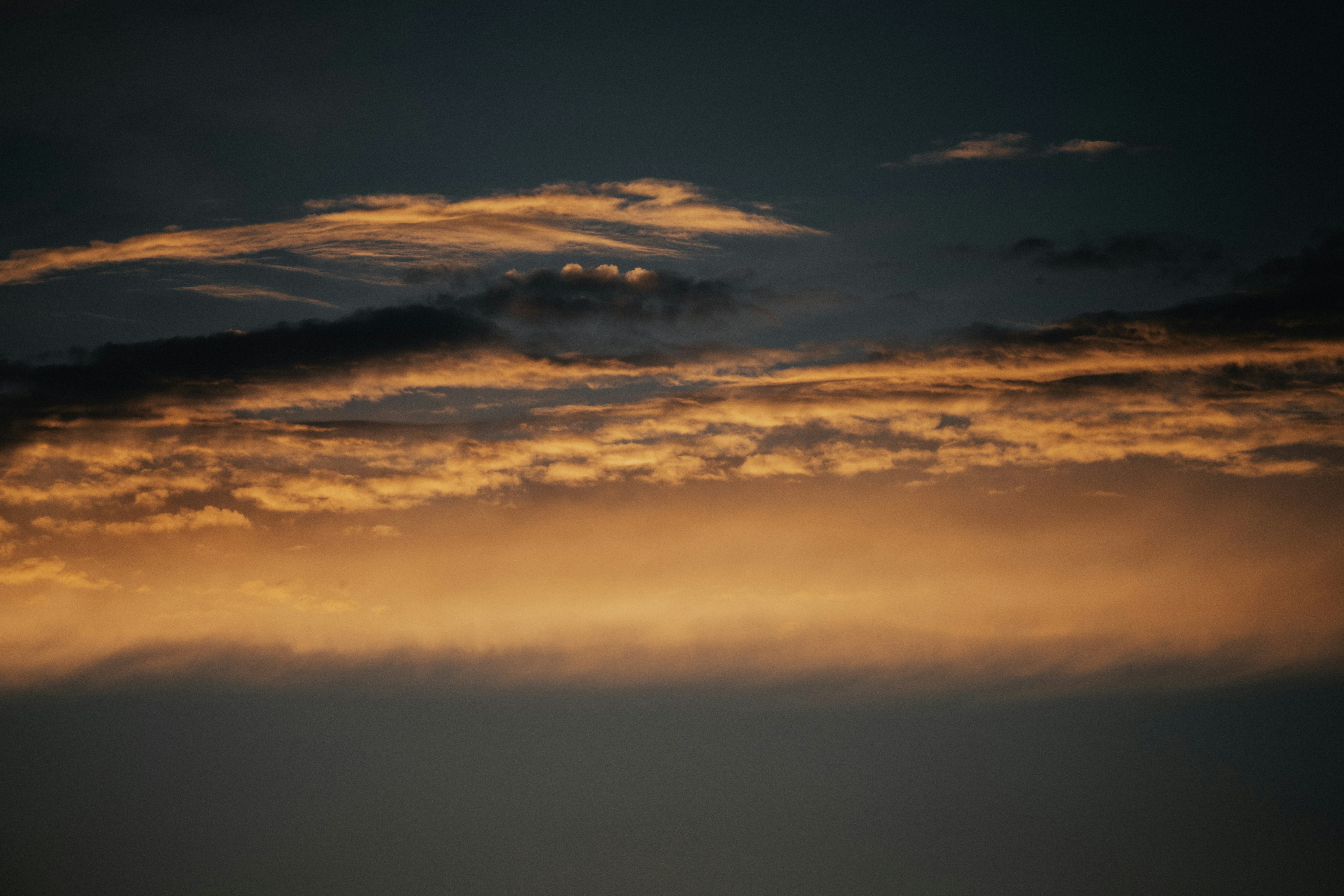 Golden clouds stretch across a darkening sky, creating a serene atmosphere at dusk.