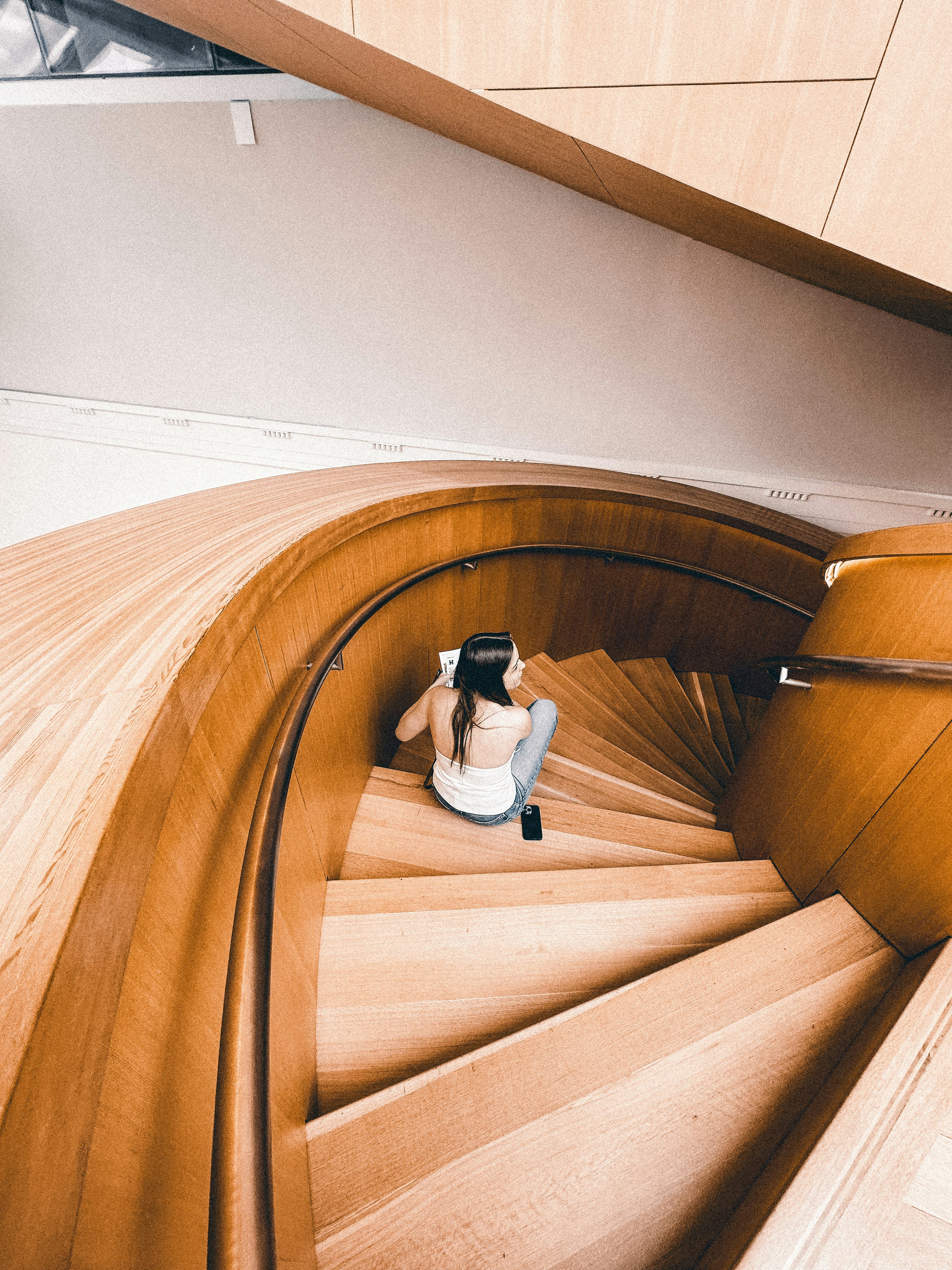 Spiral Quiet: A lone sitter pauses on the curved wooden staircase