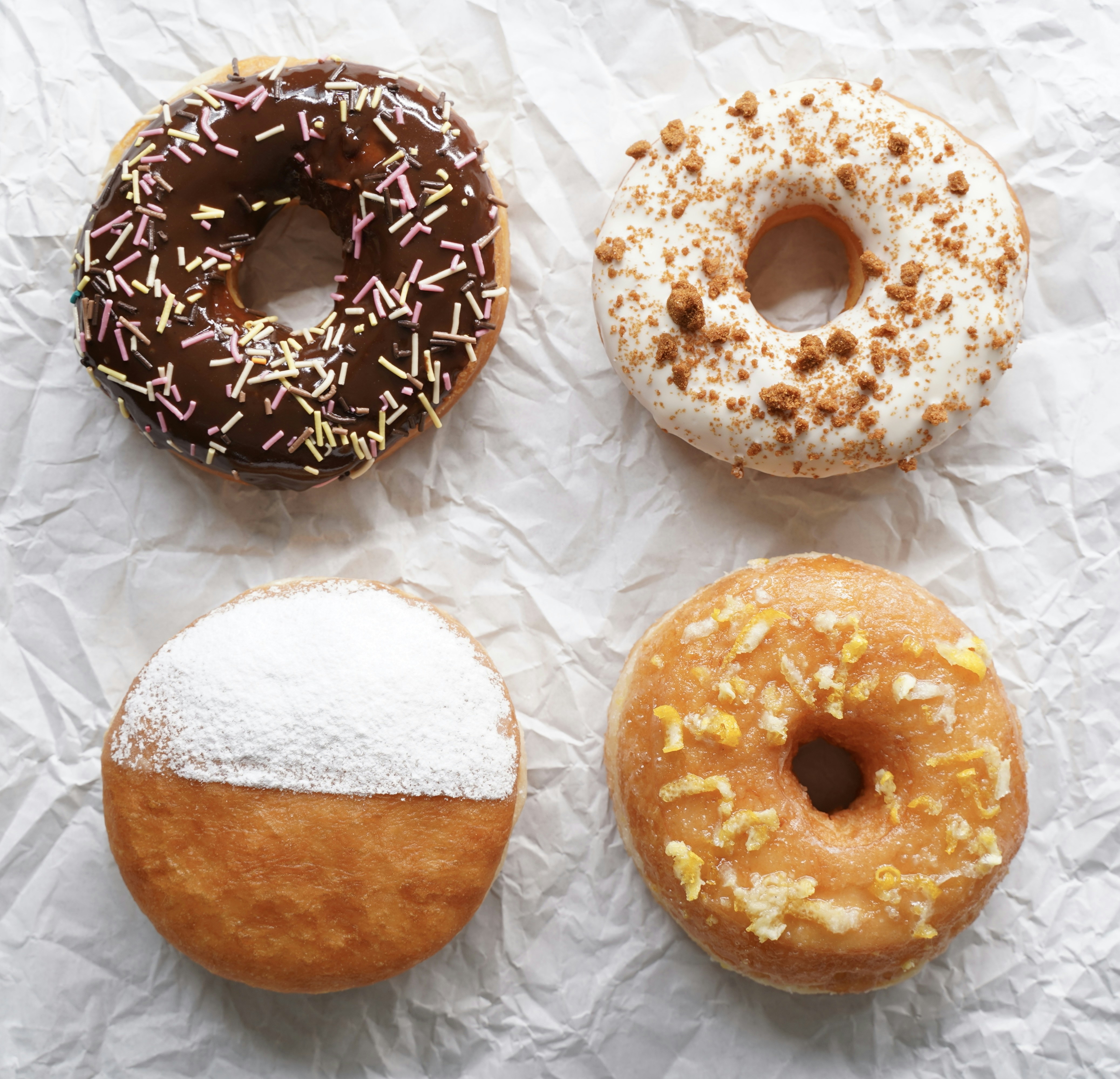 A variety of doughnuts sitting on top of a piece of paper photo – Free ...